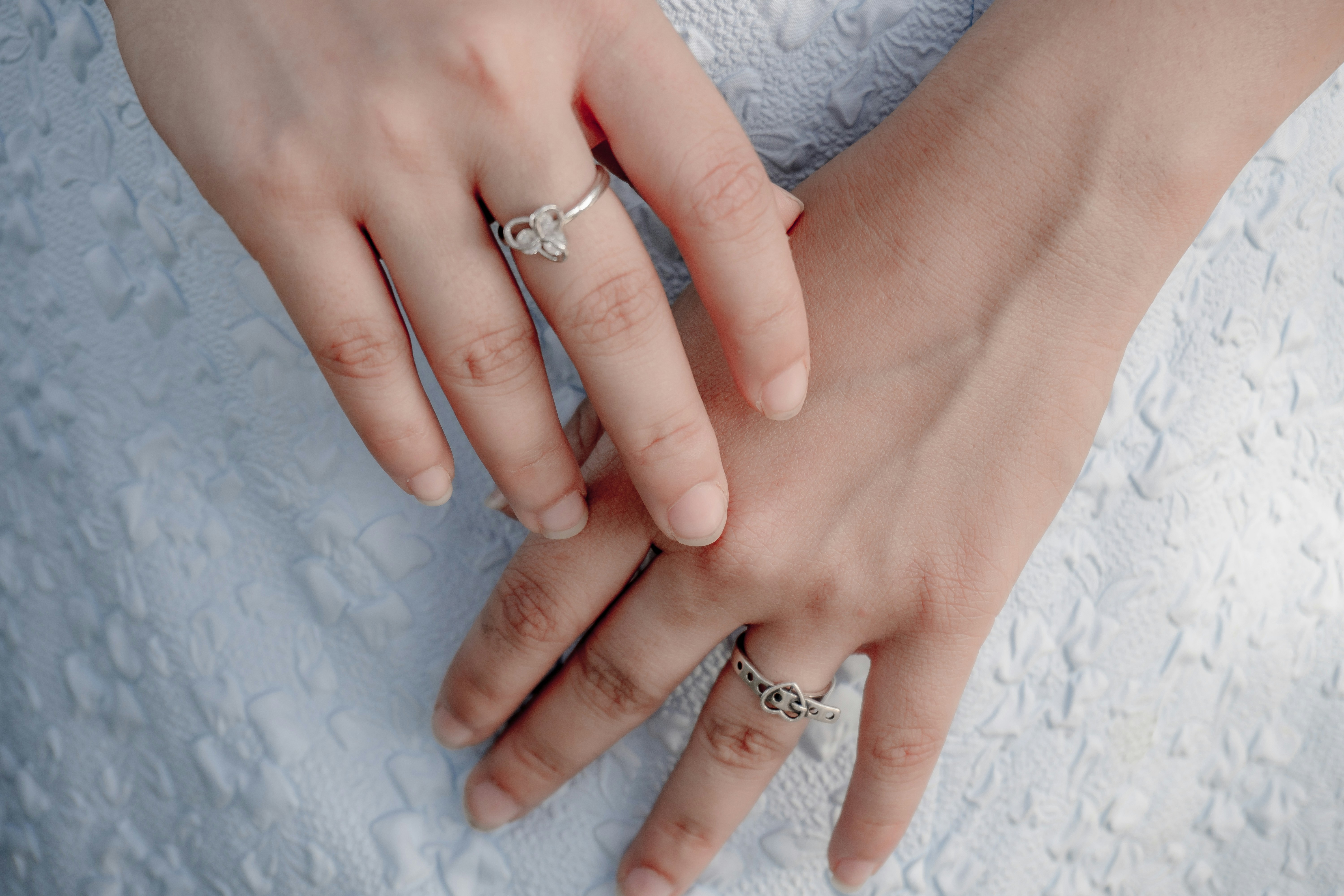 Intertwined Promise: A Close-Up of Delicate Rings on Two Hands