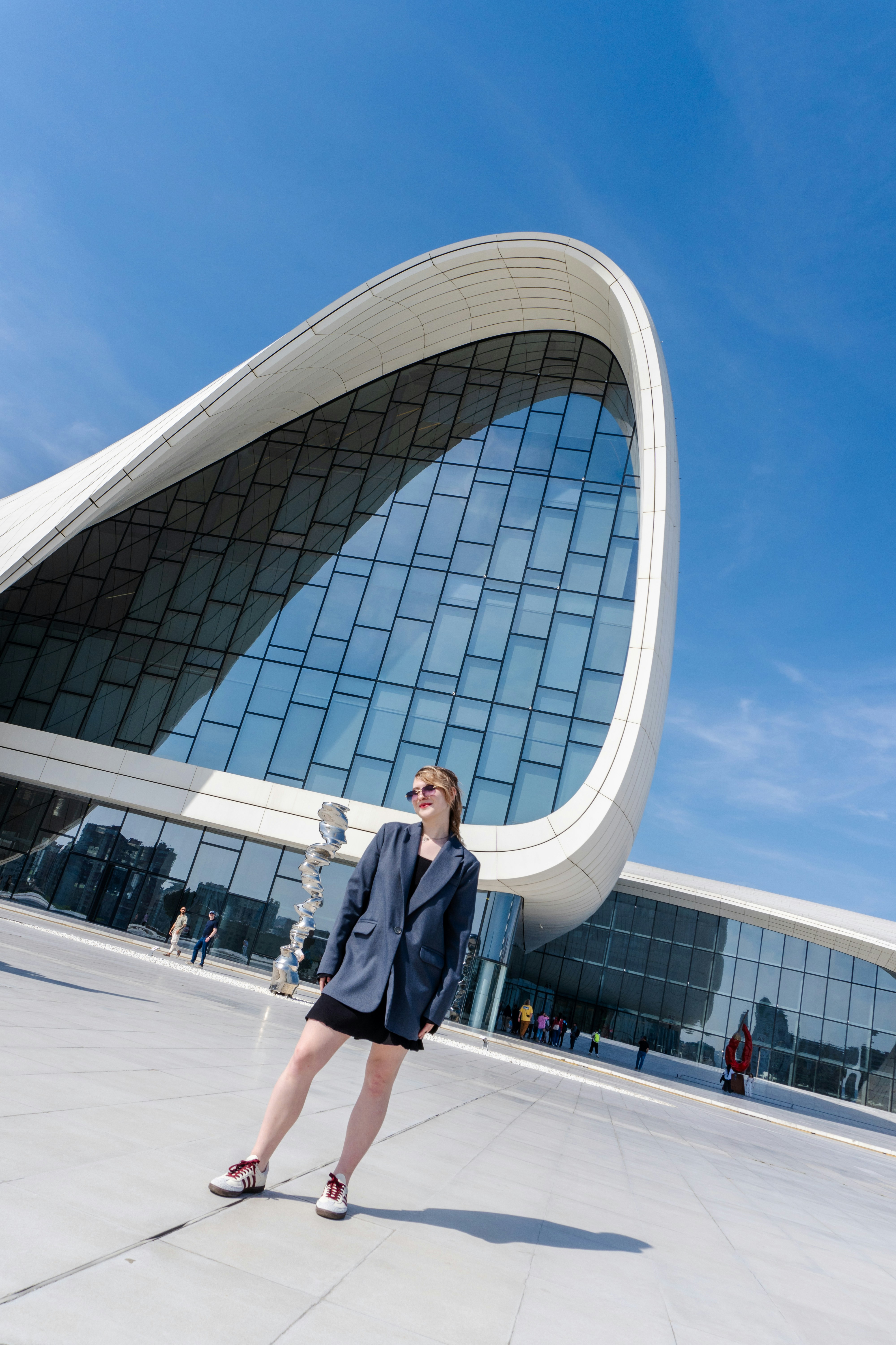 Sleek Architecture Meets City Casual: A Model Stands Before the Curved Glass Wing