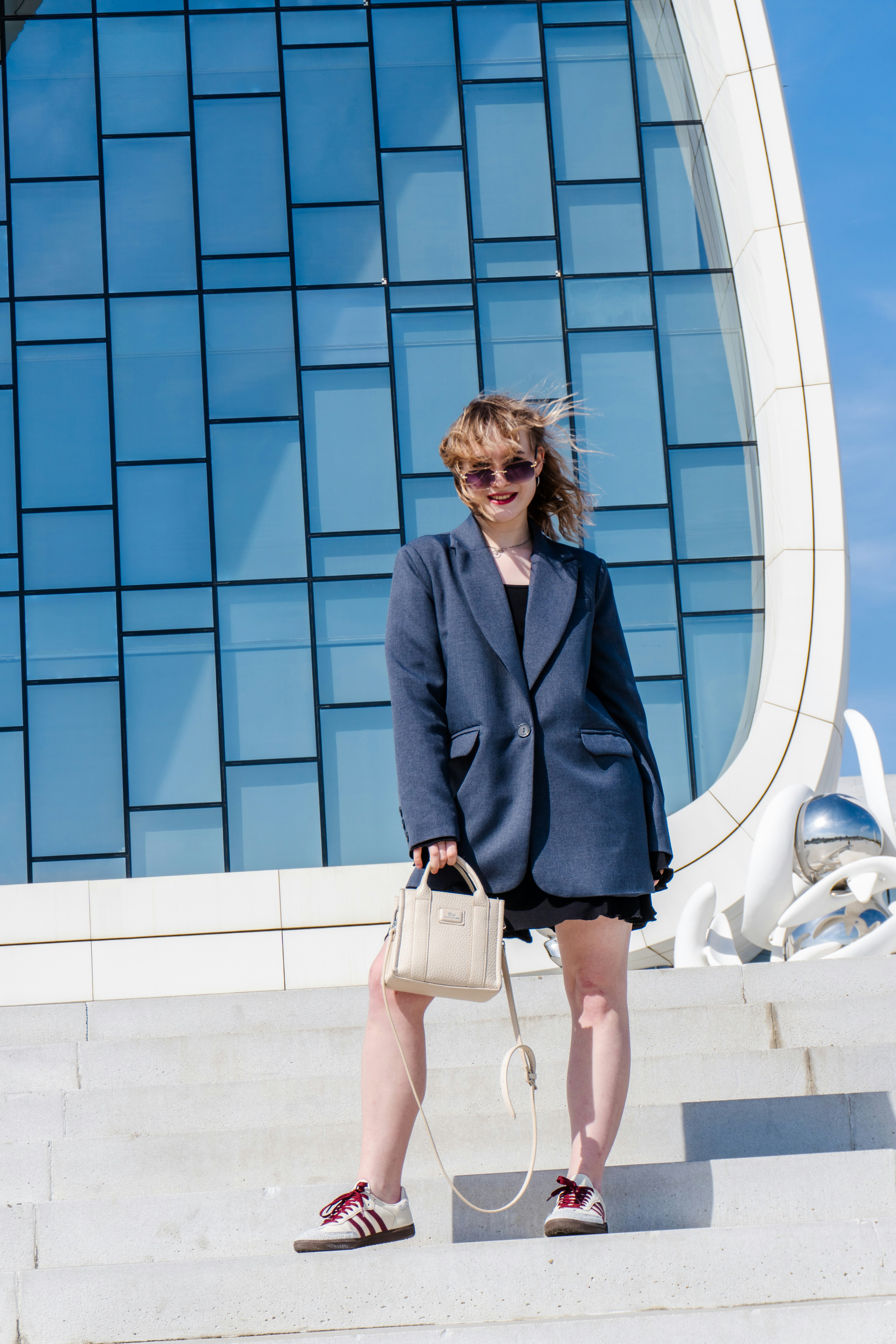 Blazer on a Glassy Stage: A Figure Steps Into the Blue Facade