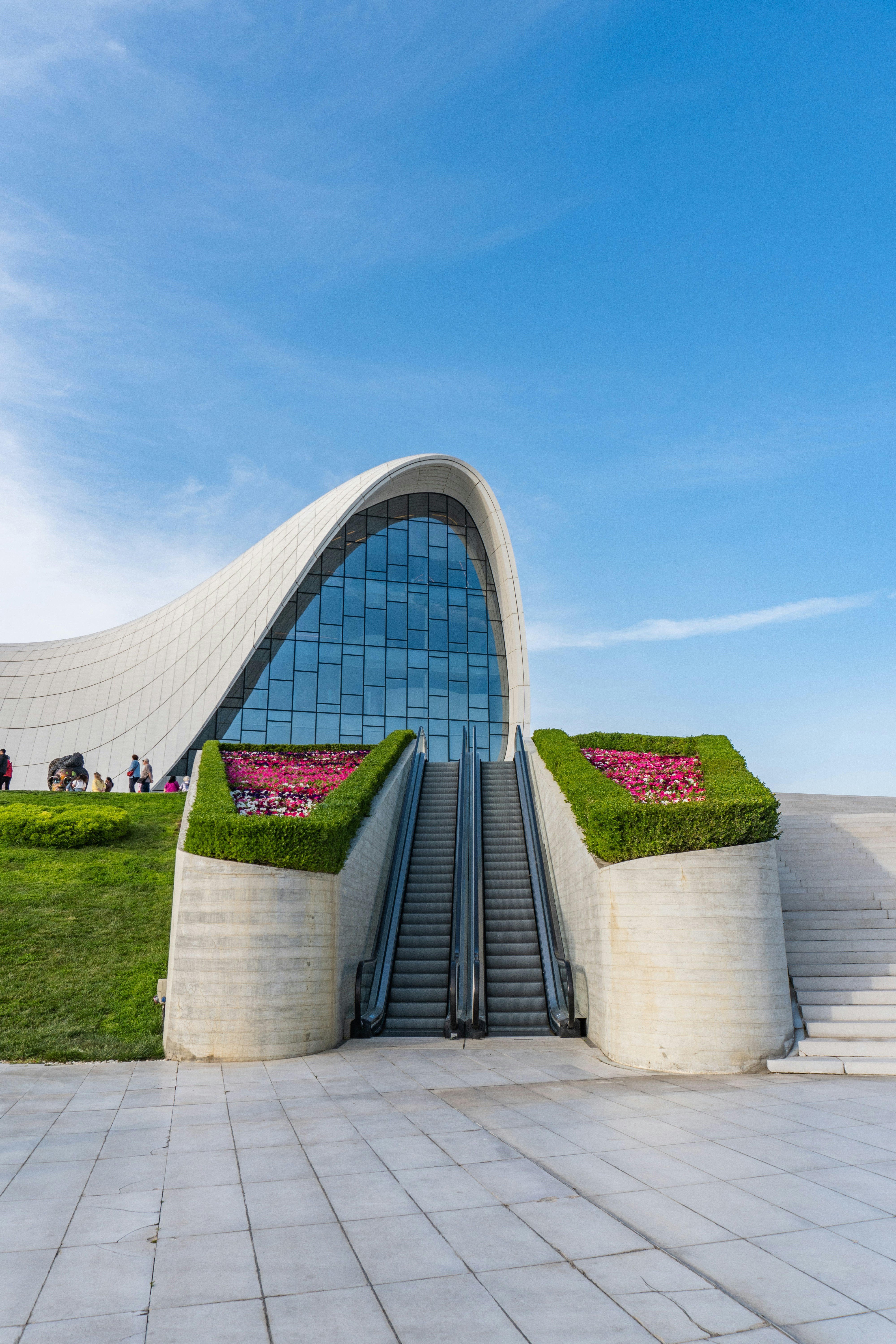 Arc Gate Over Escalators: A Glass Pavilion Framed by Greenery