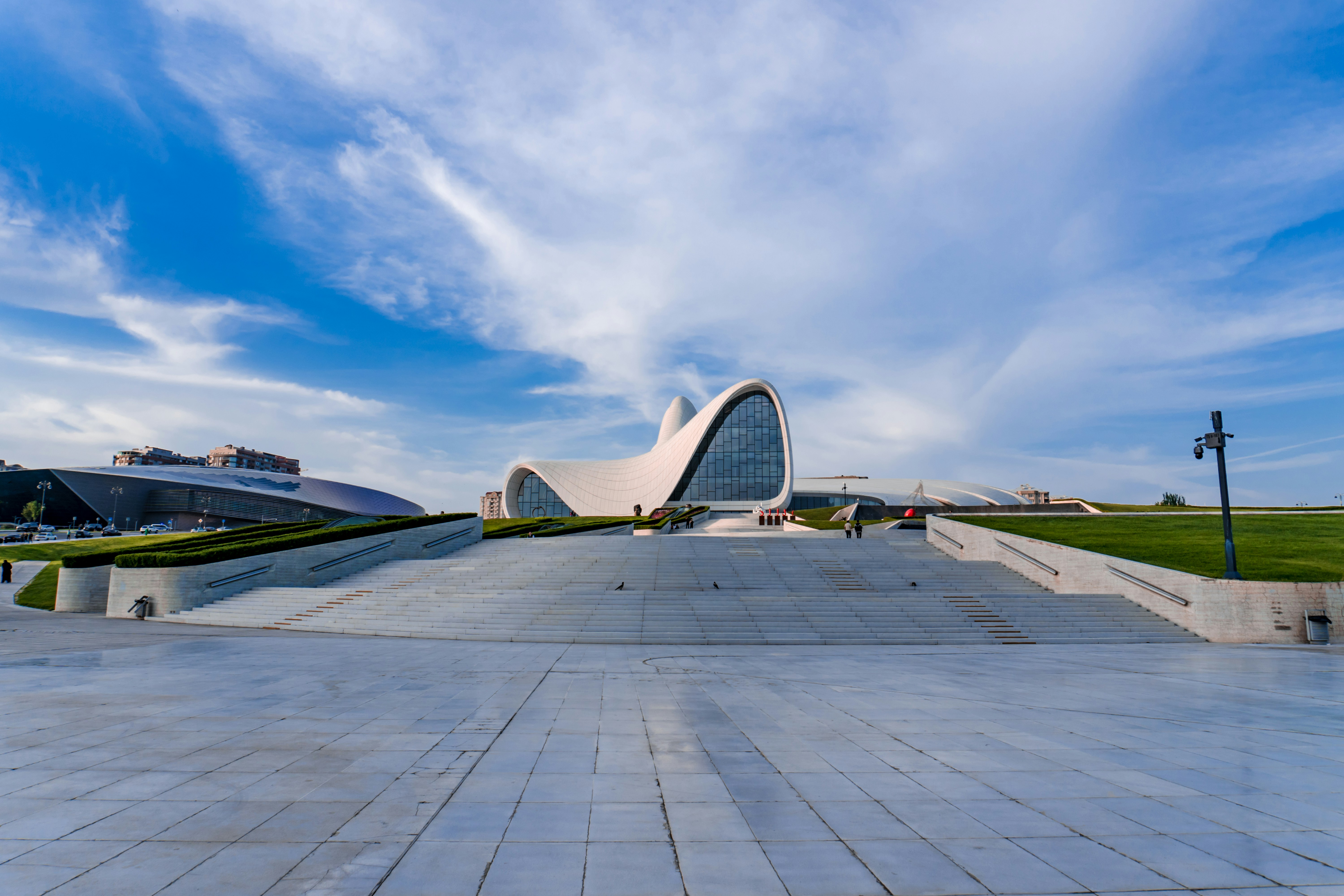 White Sculptural Pavilion at the End of a Broad Marble Plaza Under a Cerulean Sky