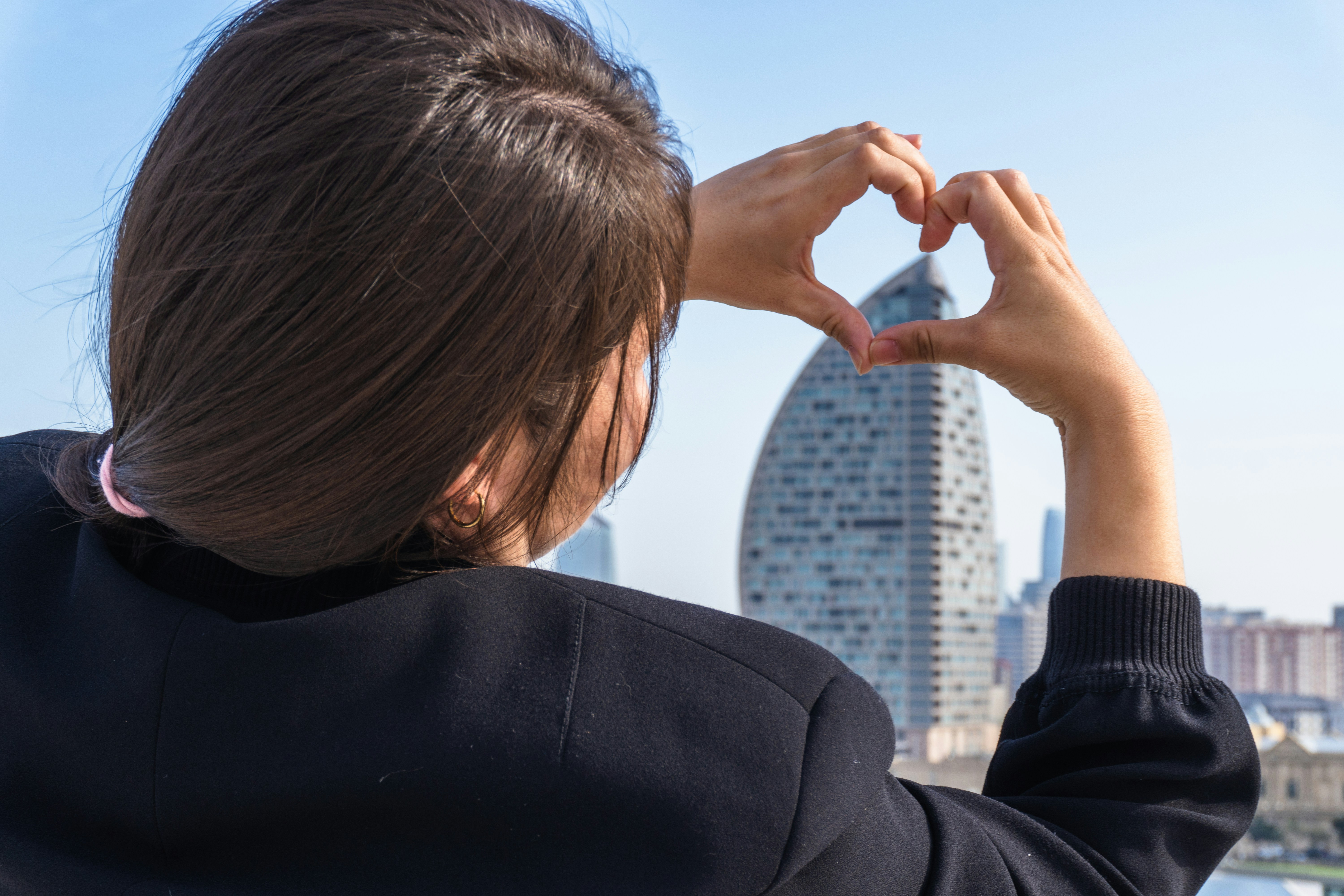 Heart of the Skyline: Framing a Modern Arch through Hands