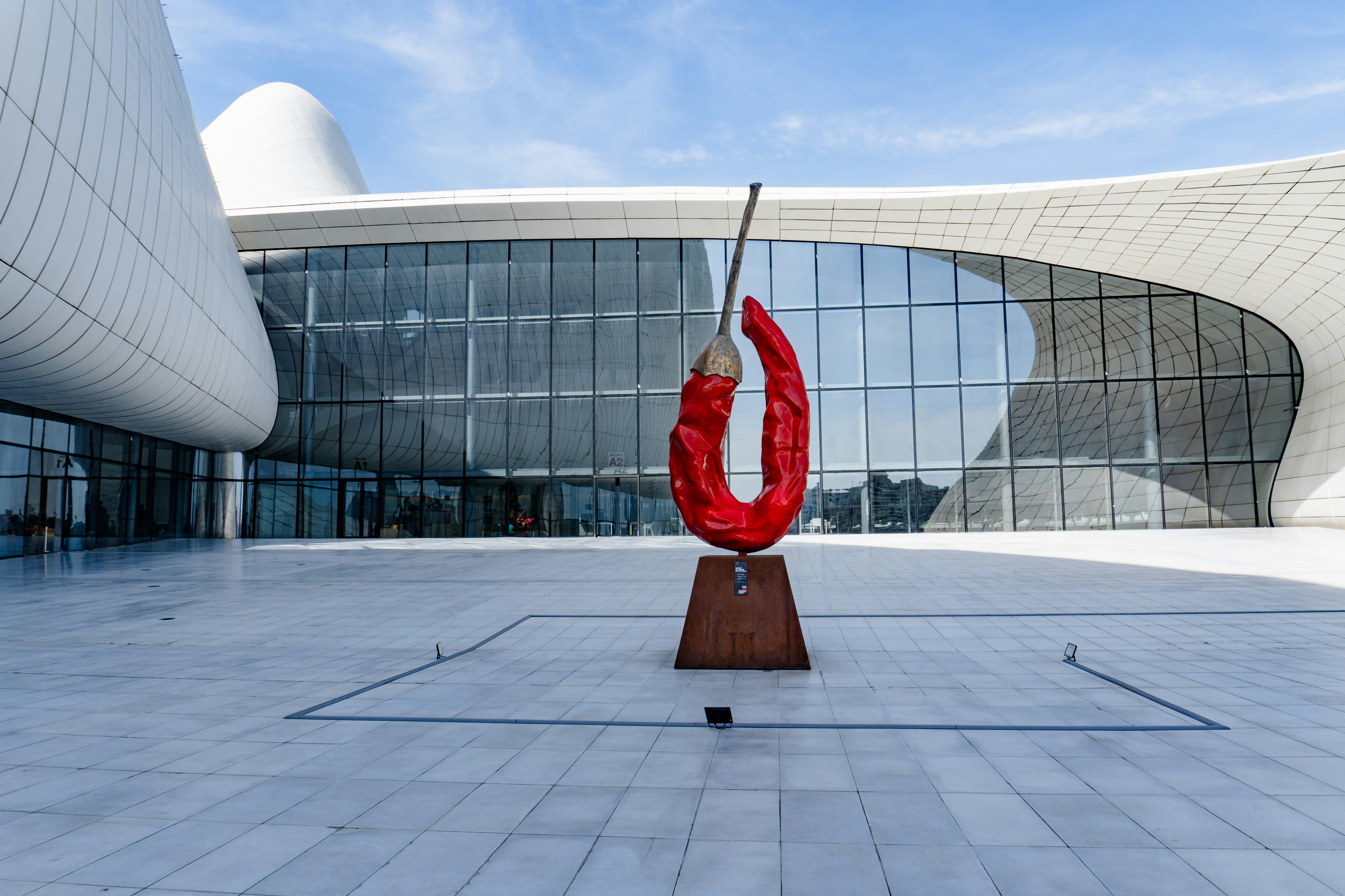 Crimson Arc Sculpted on Marble: Red Form Framed by a Glass Pavilion