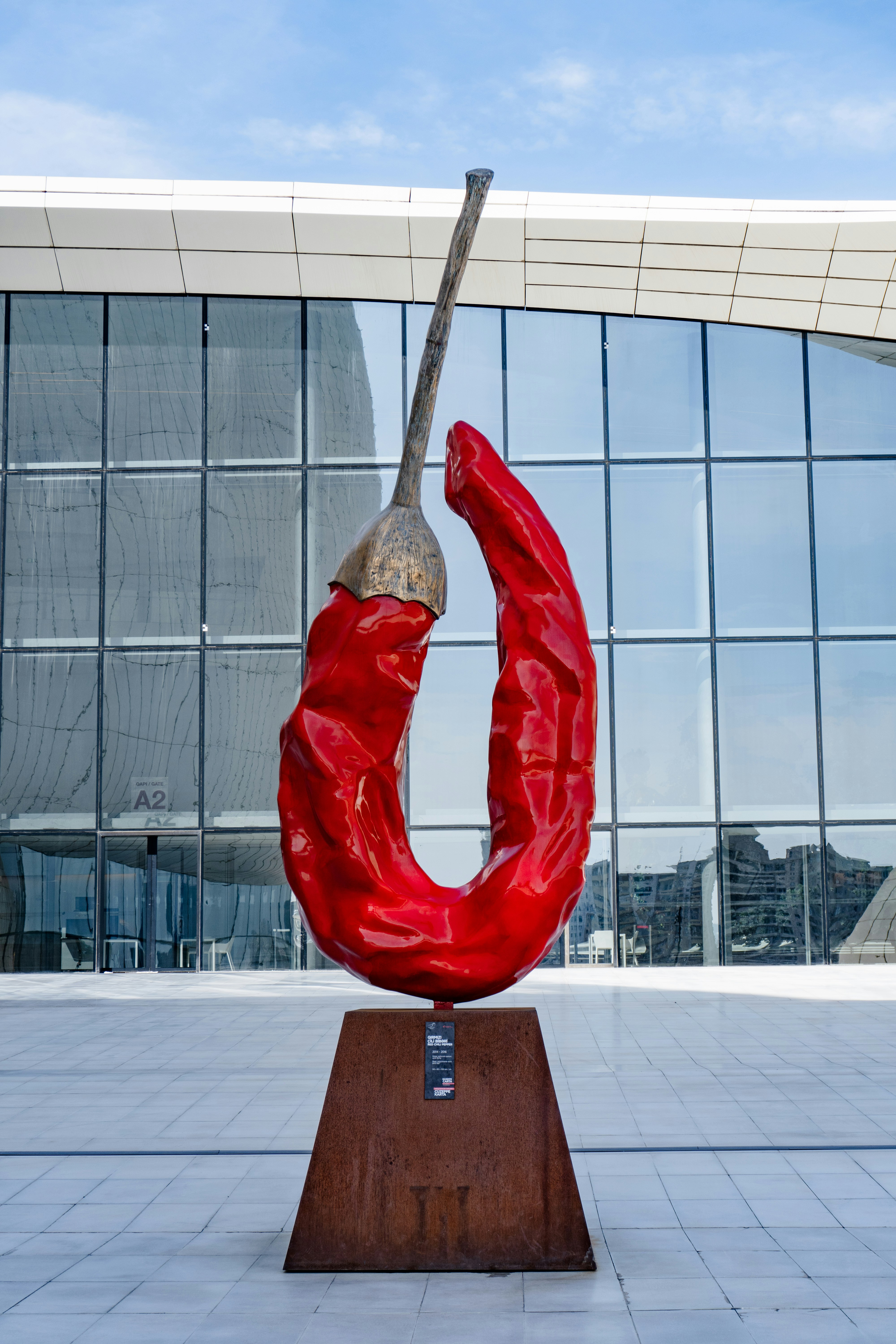 Crimson Loop: A Fiery Sculpture Framing the Modern Glass Facade