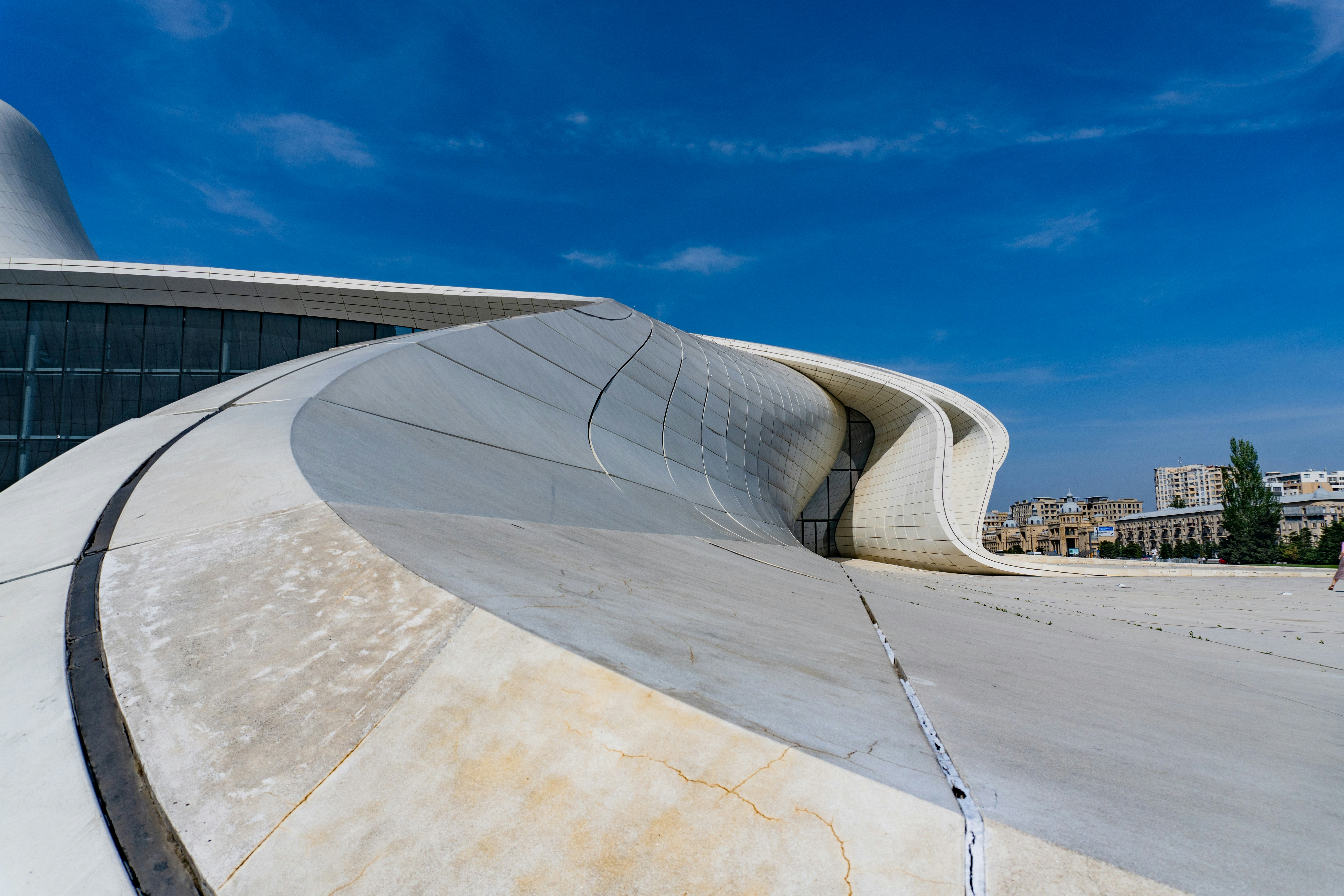 Curved concrete structure showcases modern architectural design against a clear blue sky. The flowing lines create a sense of movement and harmony.