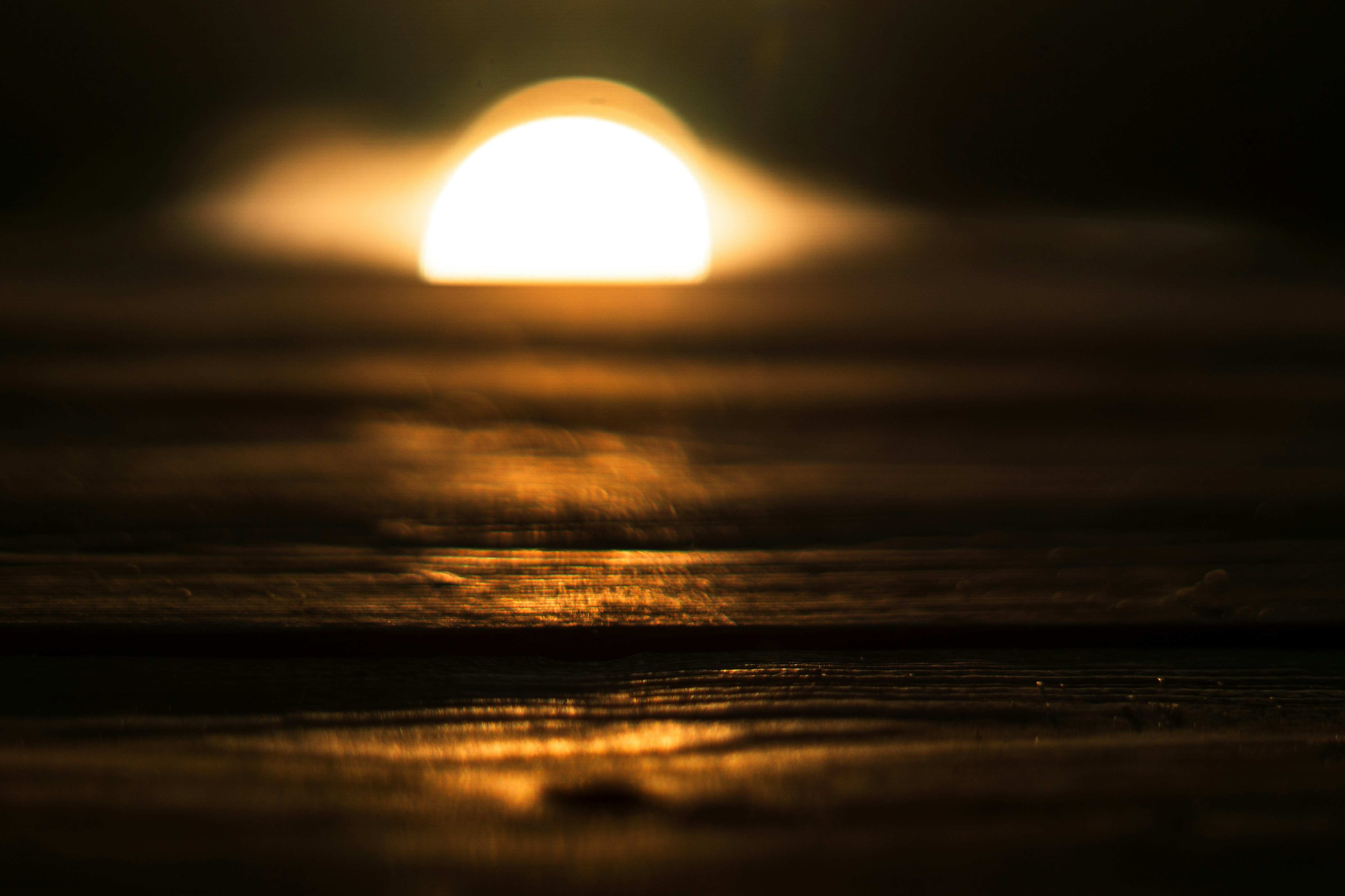 Golden sun setting on a textured surface, casting soft reflections and shadows. The scene evokes tranquility and the transition of day to night.