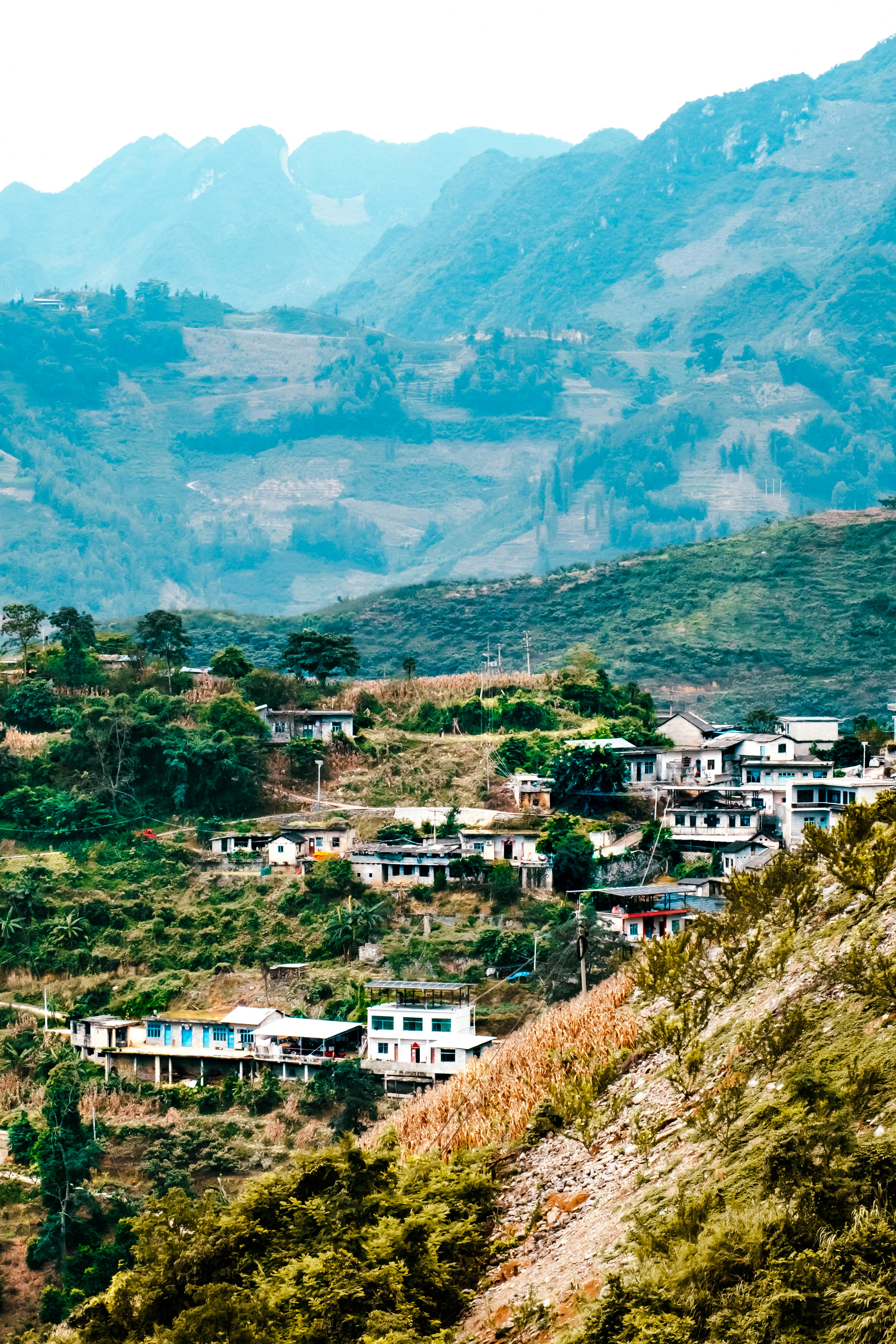 Charming hillside village surrounded by lush greenery and distant mountains. The scene captures the essence of rural life in a mountainous region.