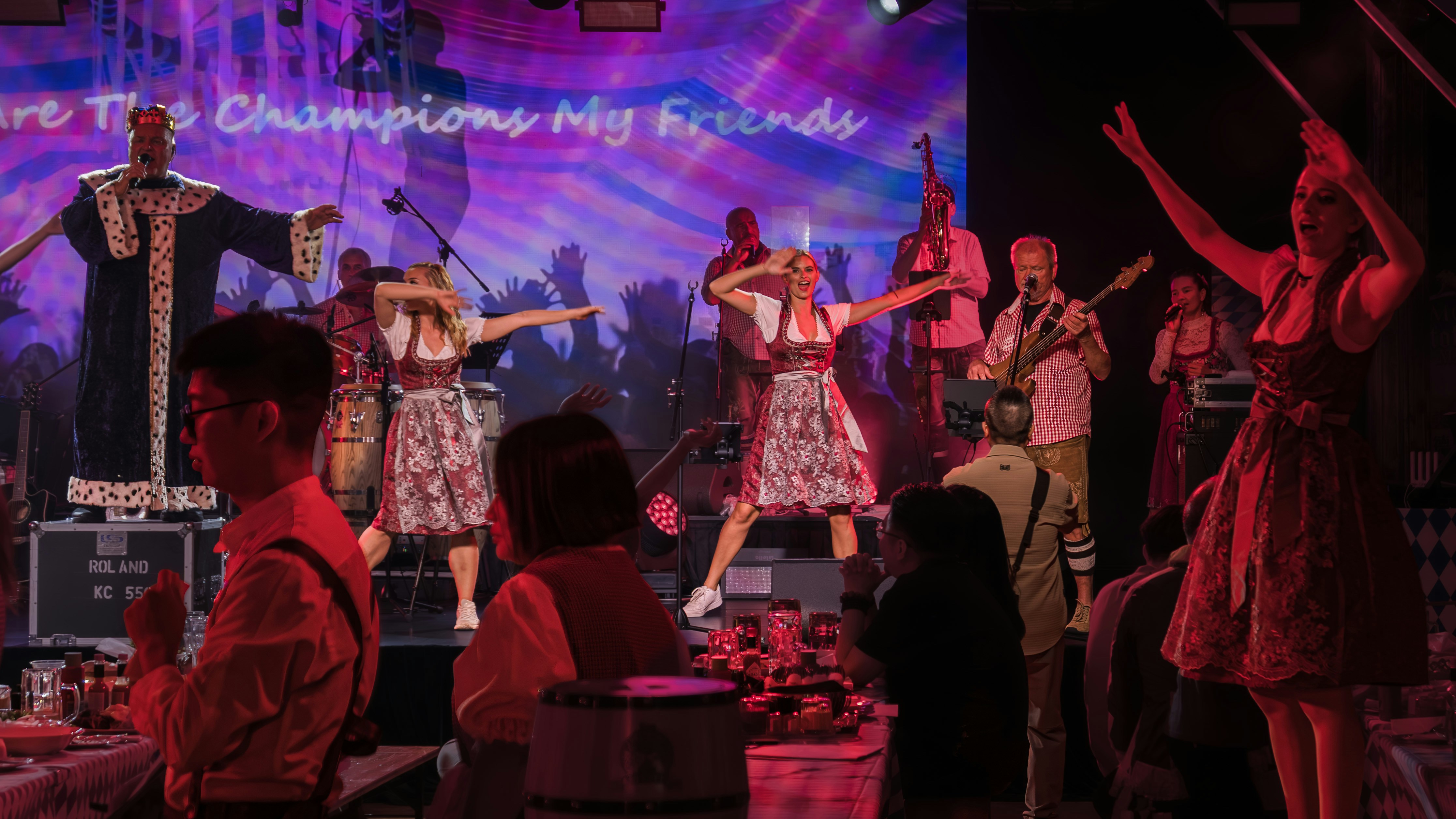 Band performs on stage with dancers at a lively event