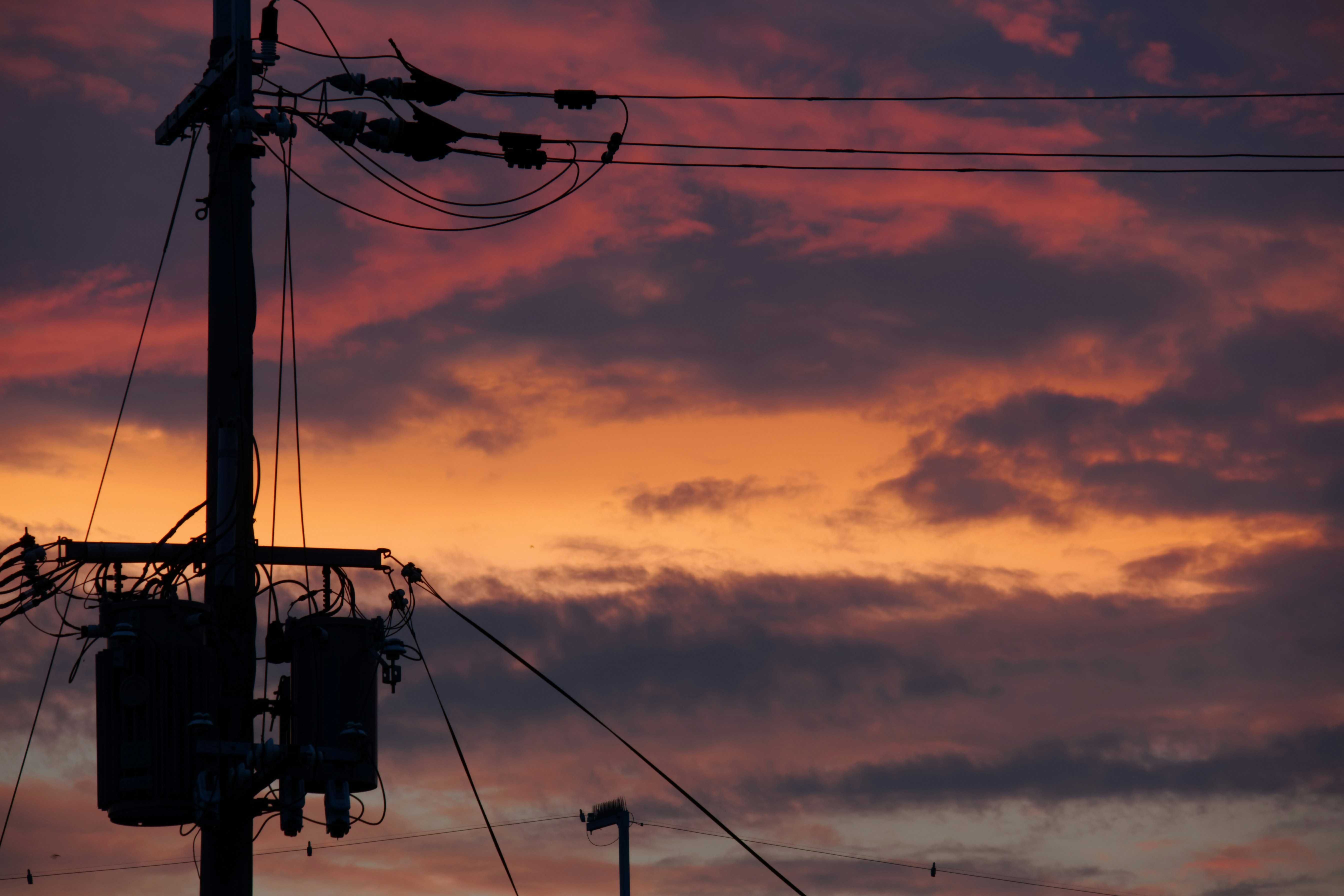 Dusk Grid: Silhouetted Utility Pole Against a Fiery Horizon
