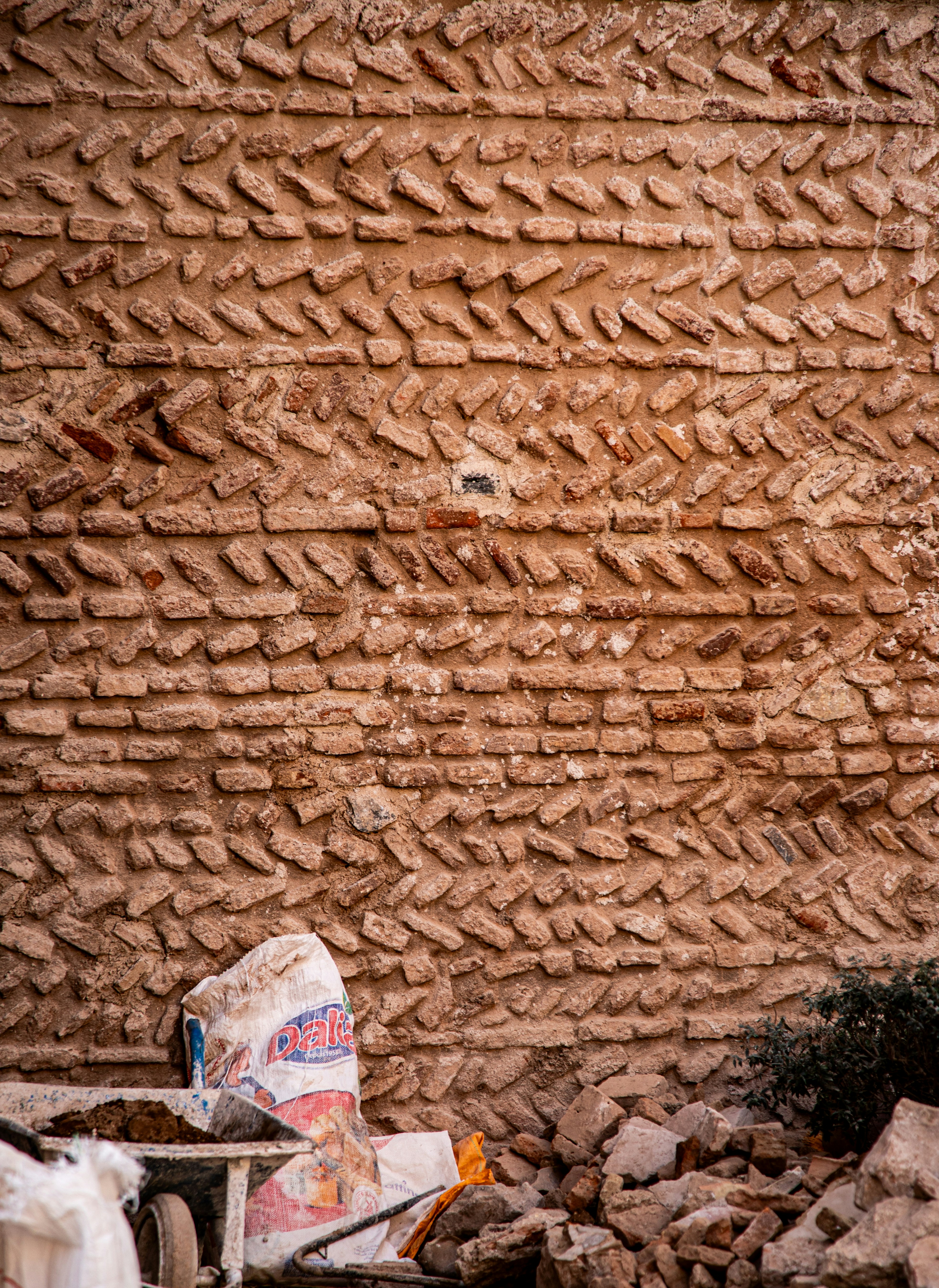 Ground-Level Texture Study: Weathered Brick Facade and Rubble at the Wall's Base