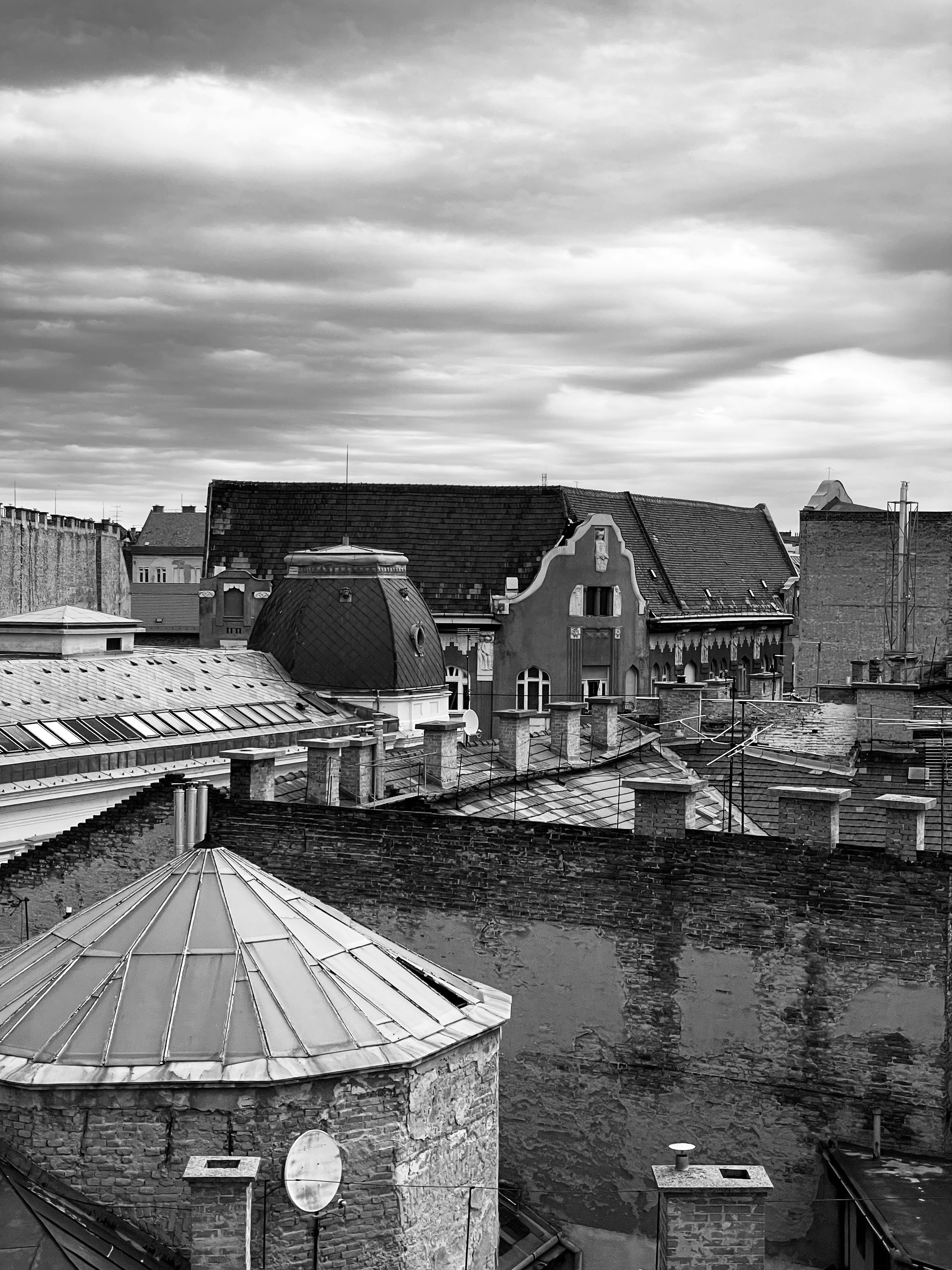 Rooftops and chimneys under a cloudy sky.
