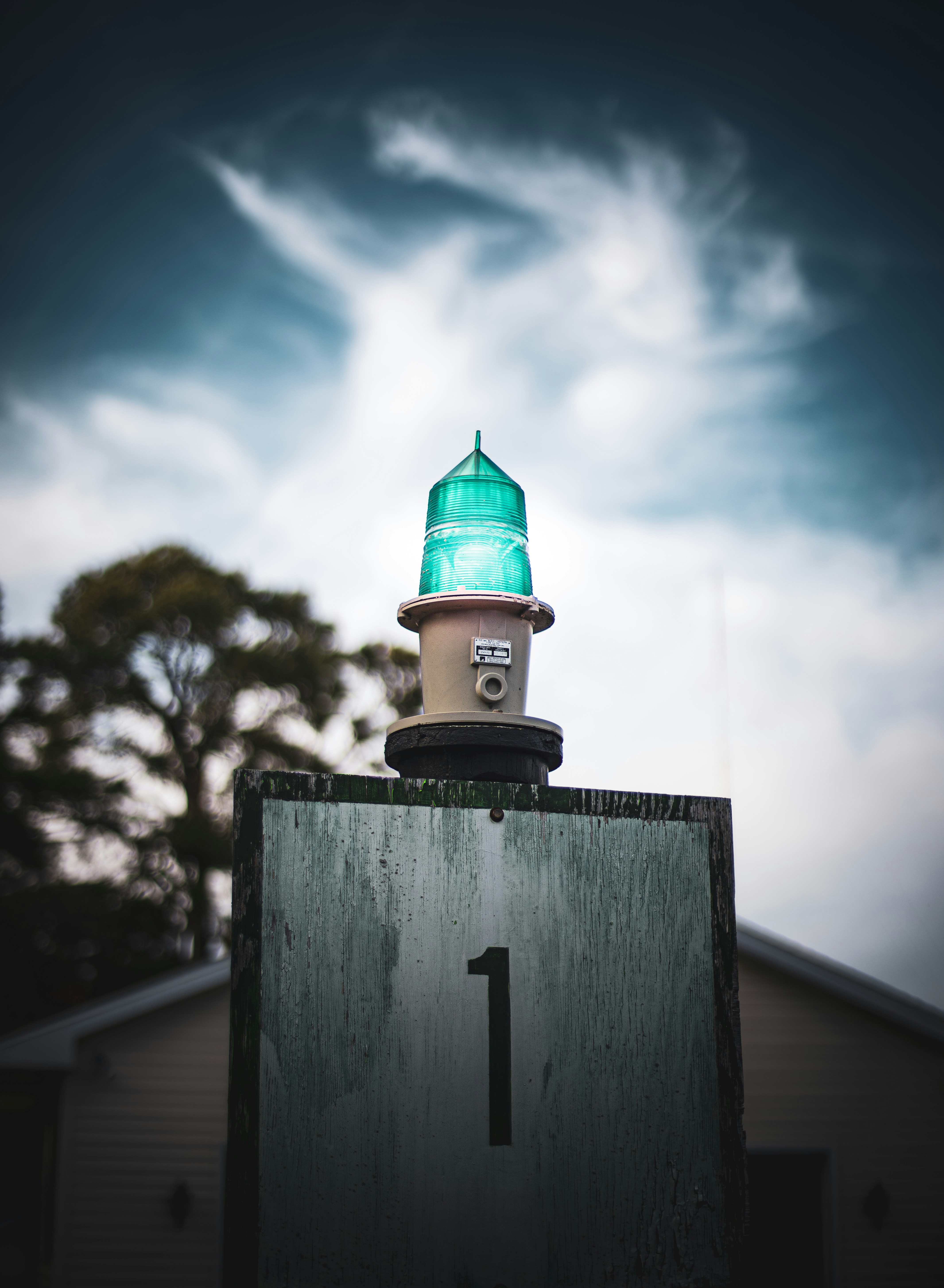 Teal Beacon on a Weathered Post: A Quiet Sentinel Against an Overcast Sky