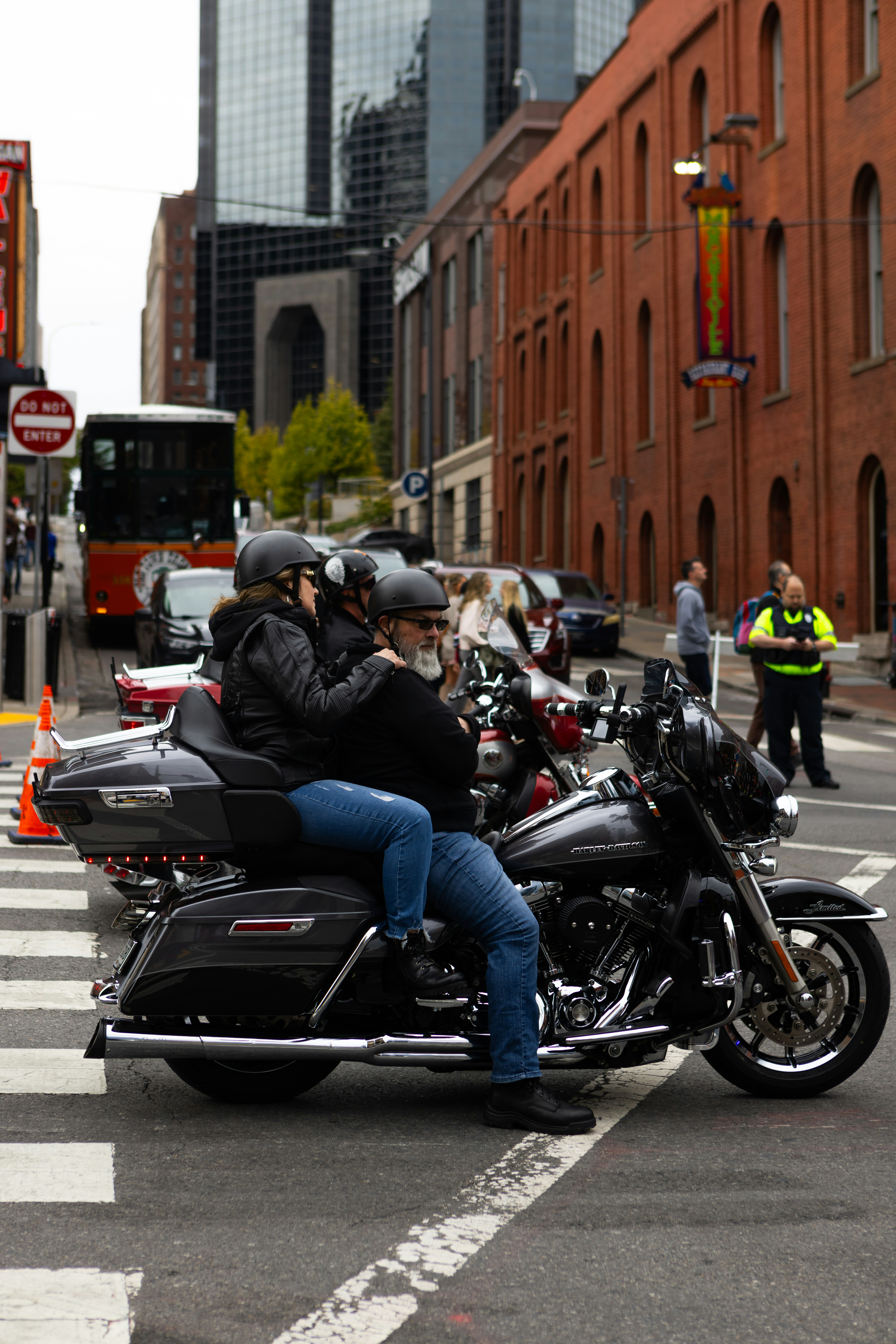Crosswalk Pause: Two Riders on a Black Touring Motorcycle in an Urban Corridor