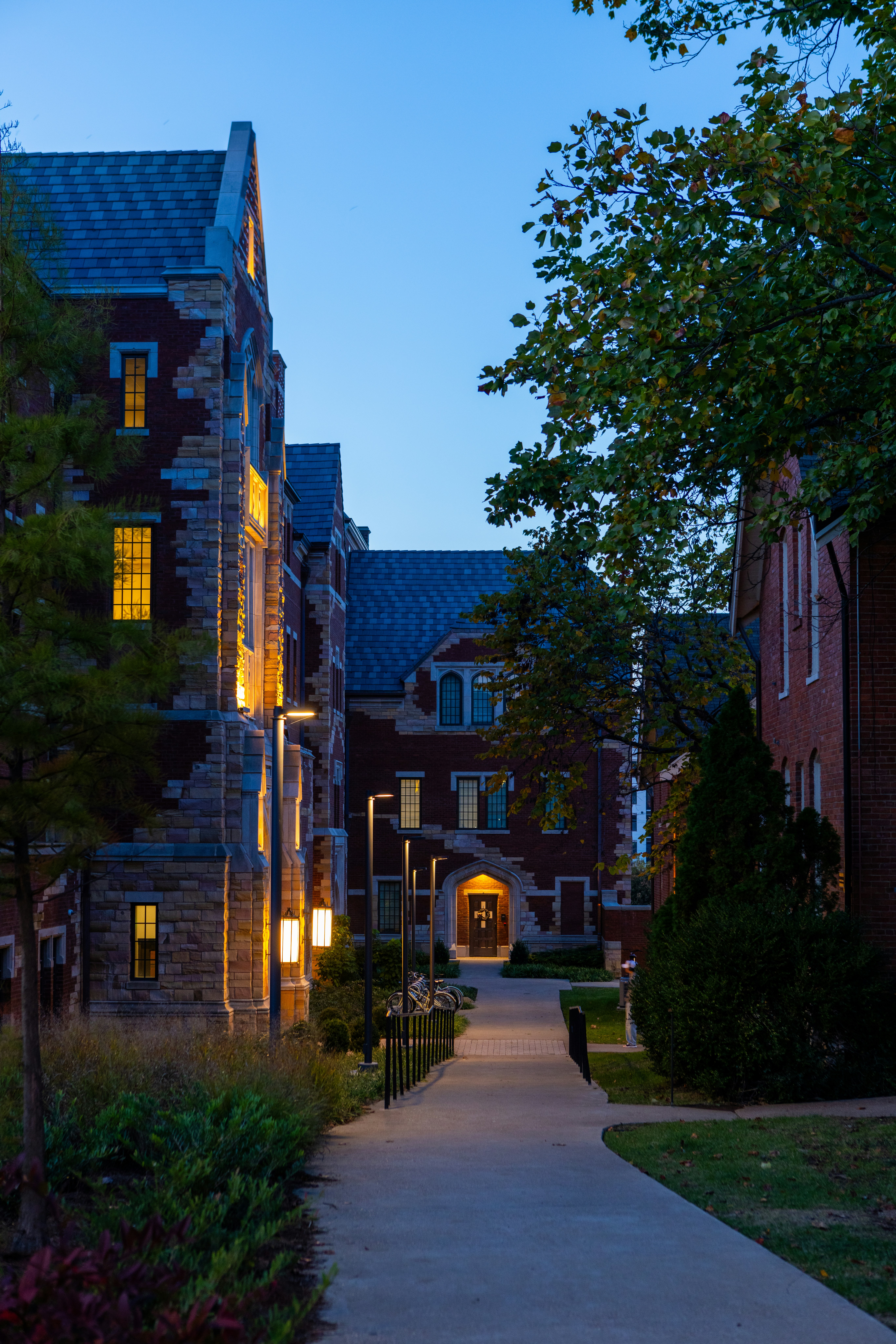 Blue Hour Lanterns Lead the Brick-Campus Walkway to a Central Arch
