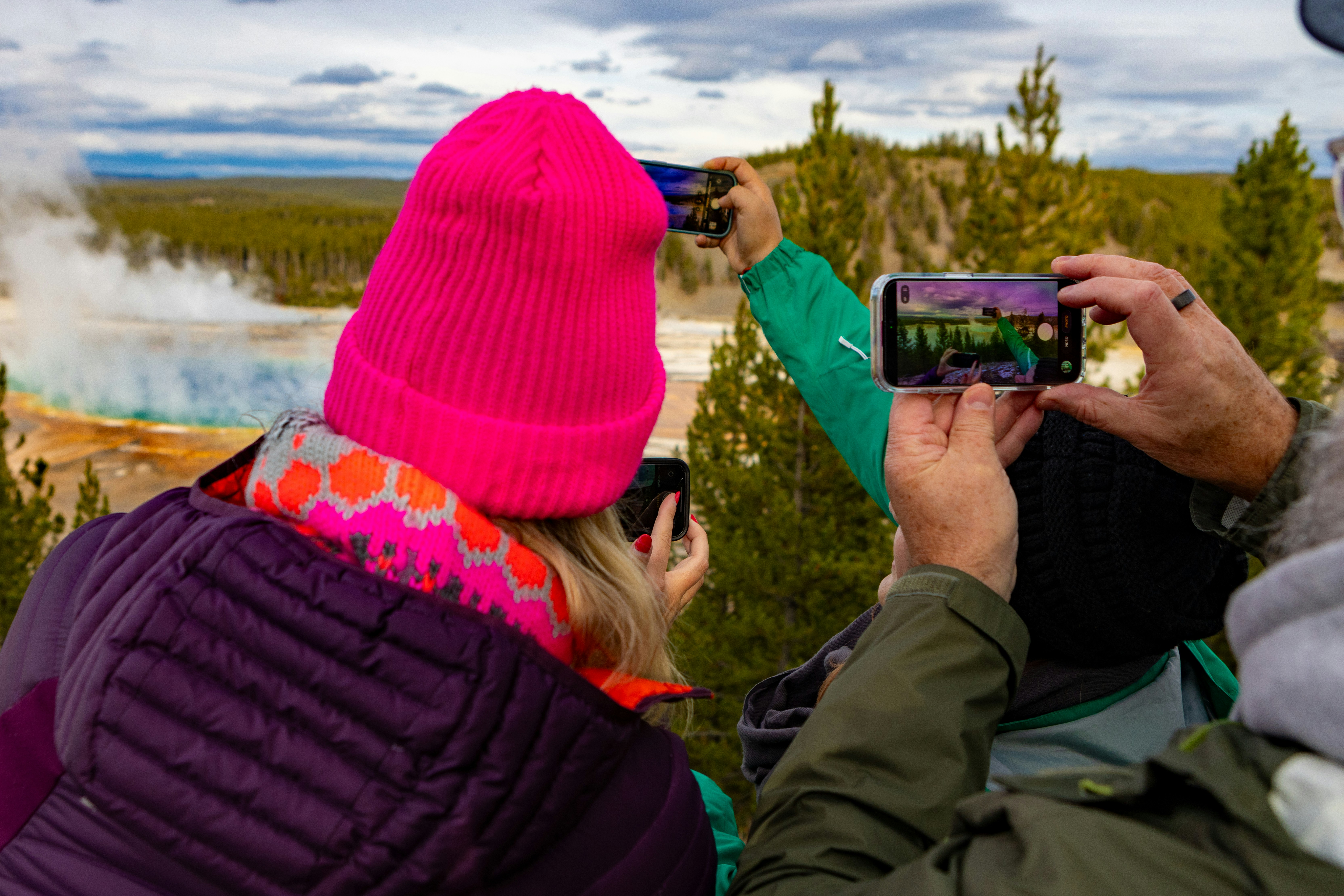 Bright Beanies and Steam: Tourists Capture a Turquoise Geothermal Pool Scene