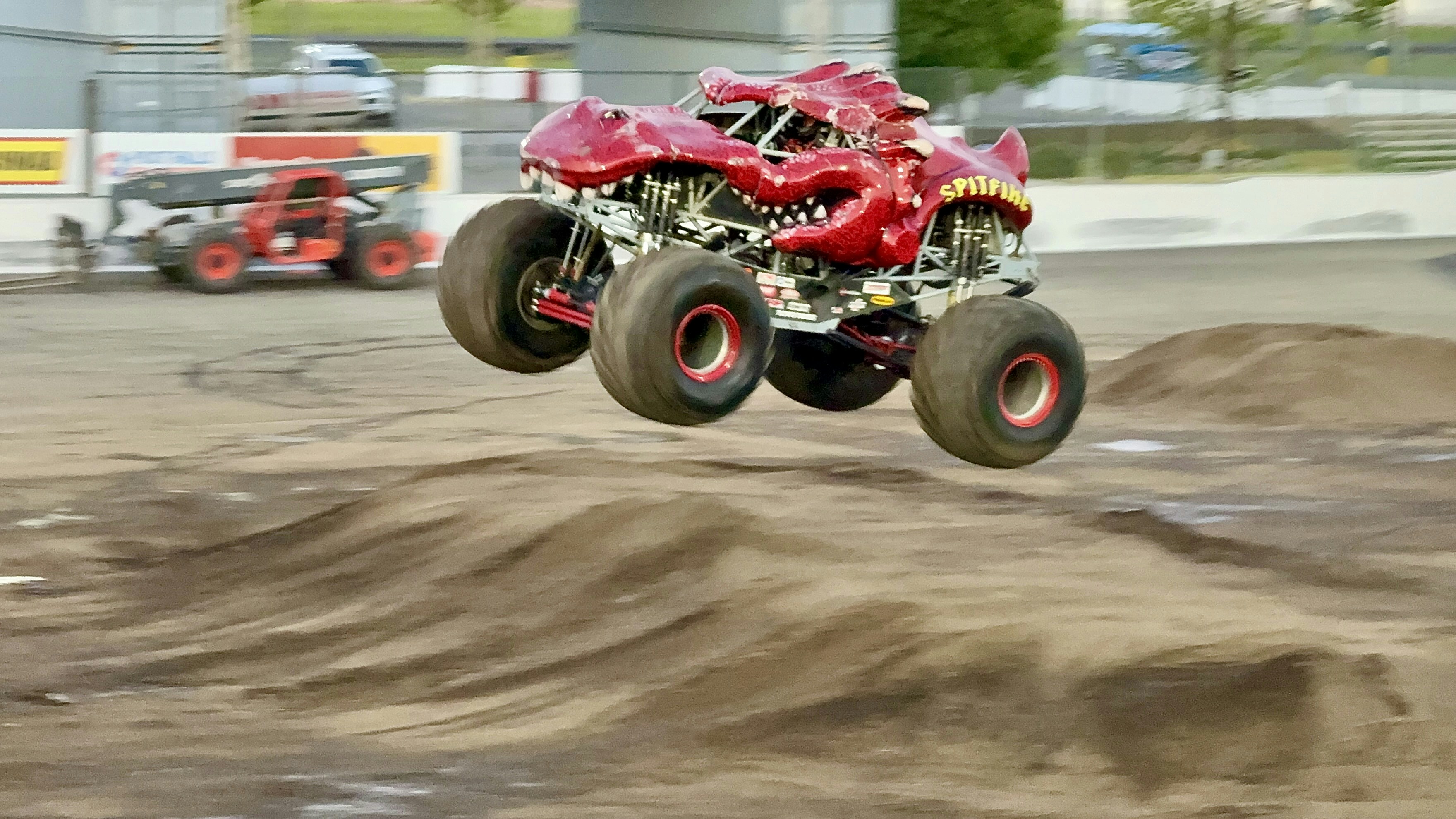 Crimson Behemoth in Mid-Air Over Dusty Berm