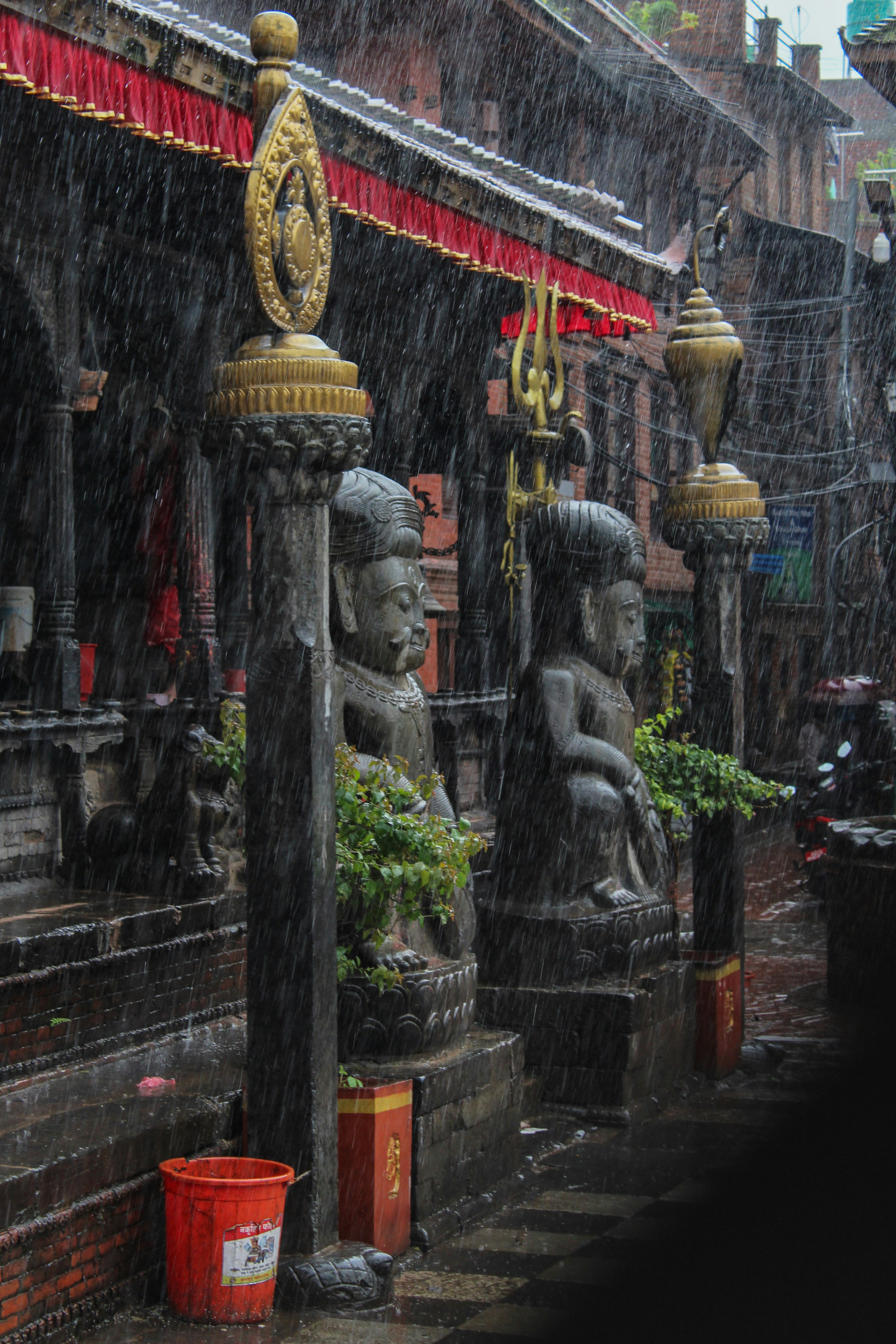 Rain-Slicked Guardians: A Temple Corridor of Stone Statues under gilded Finials