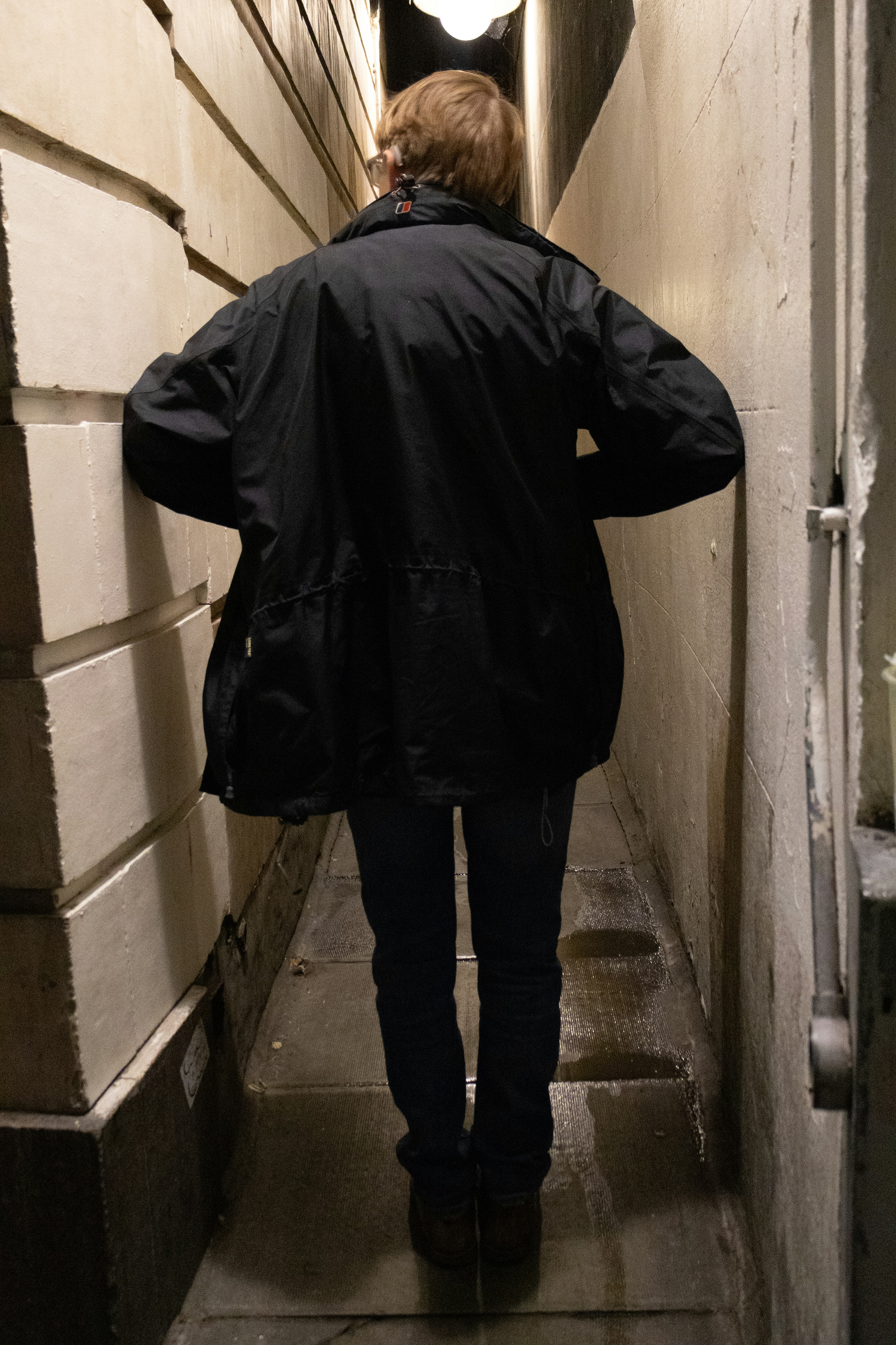 Between Stone Walls, a Figure Walks Toward a Distant Light