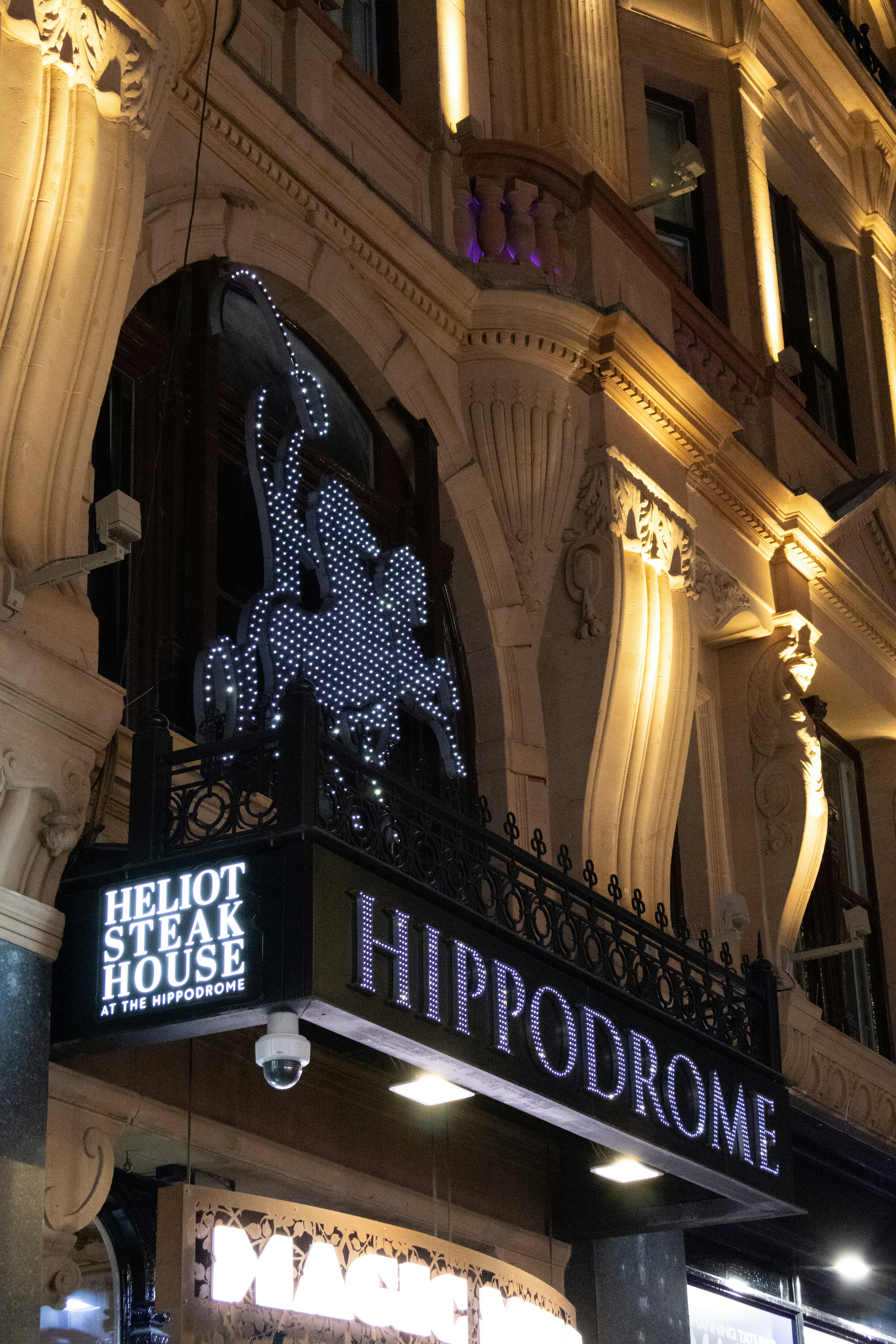 Neon Script and Stone: A Hippodrome Night Facade
