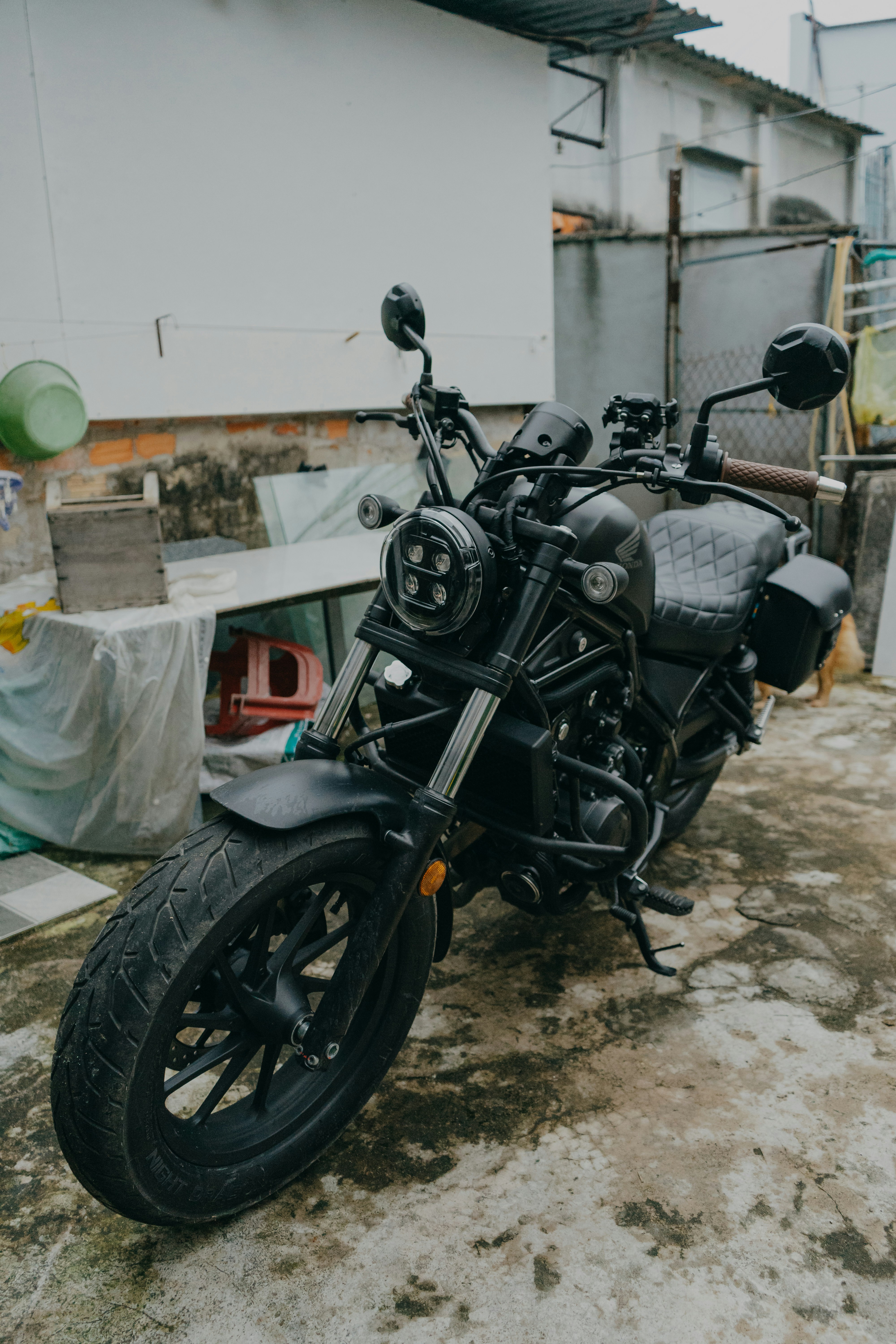 Midnight Iron in a Weathered Courtyard: A Matte-Black Motorcycle Among Tools