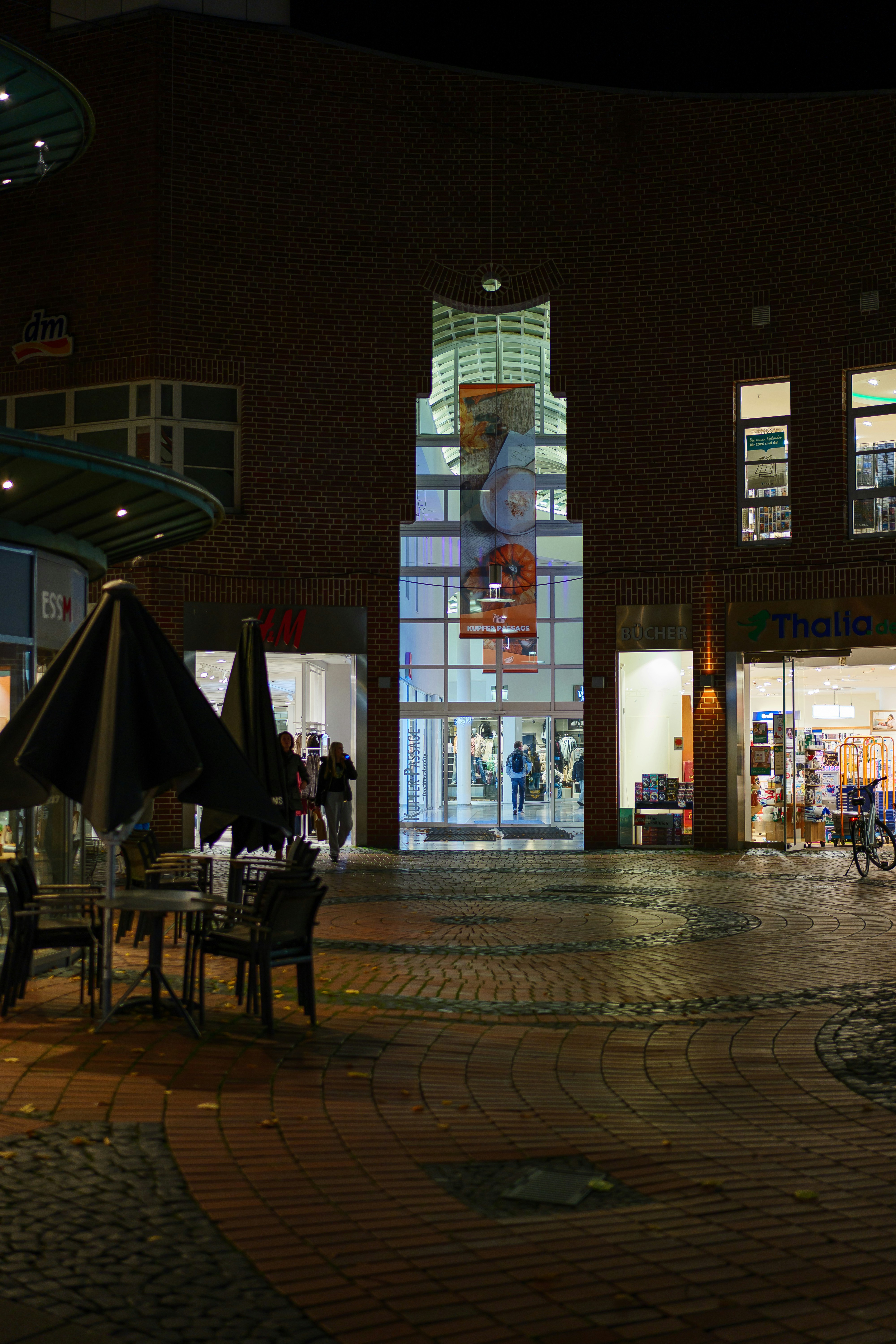 Centerframe Glass Atrium: Night Glimmer Through Brick Facades
