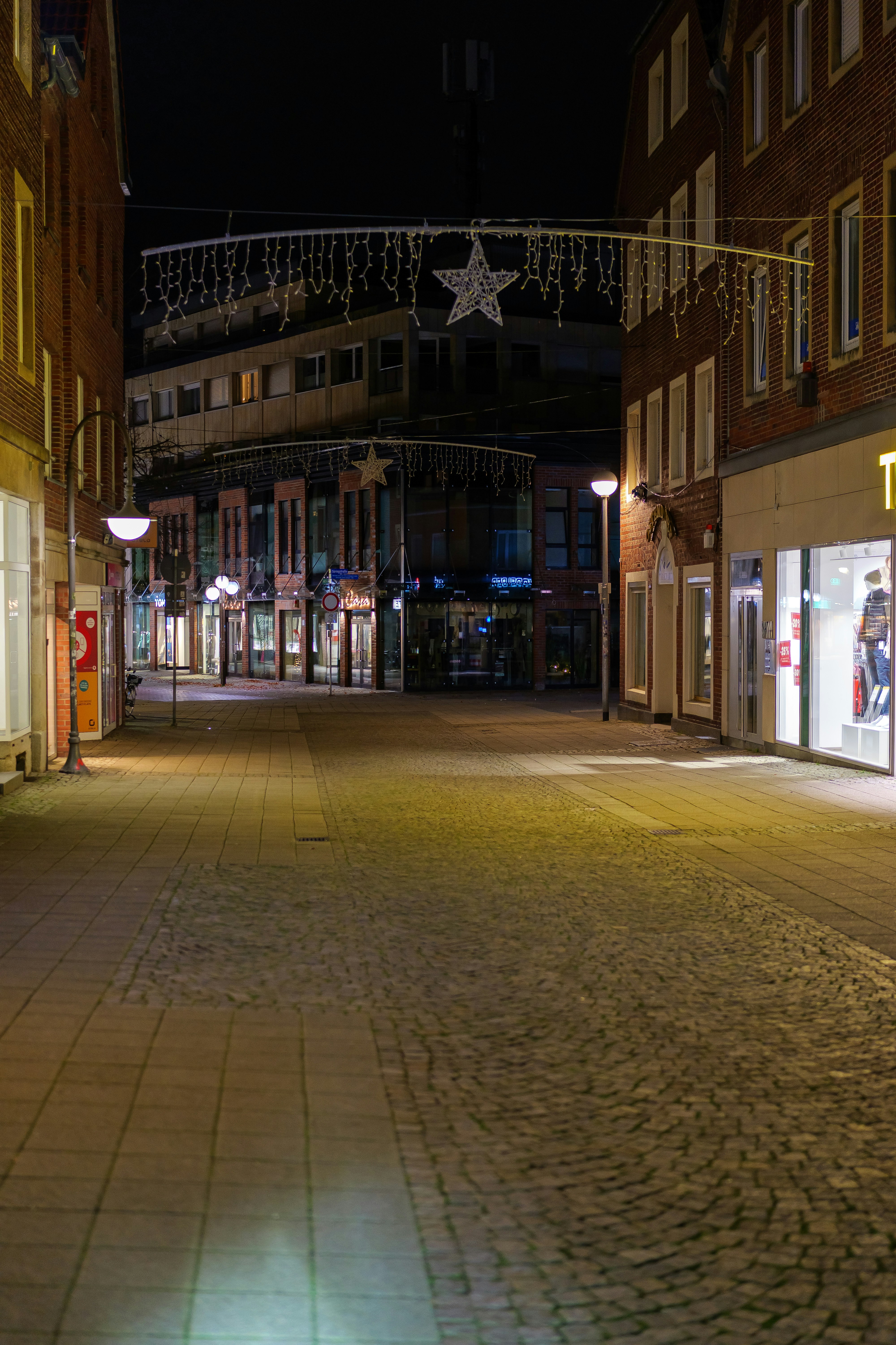 Cobblestone Quiet: Night Street Framed by Holiday Lights