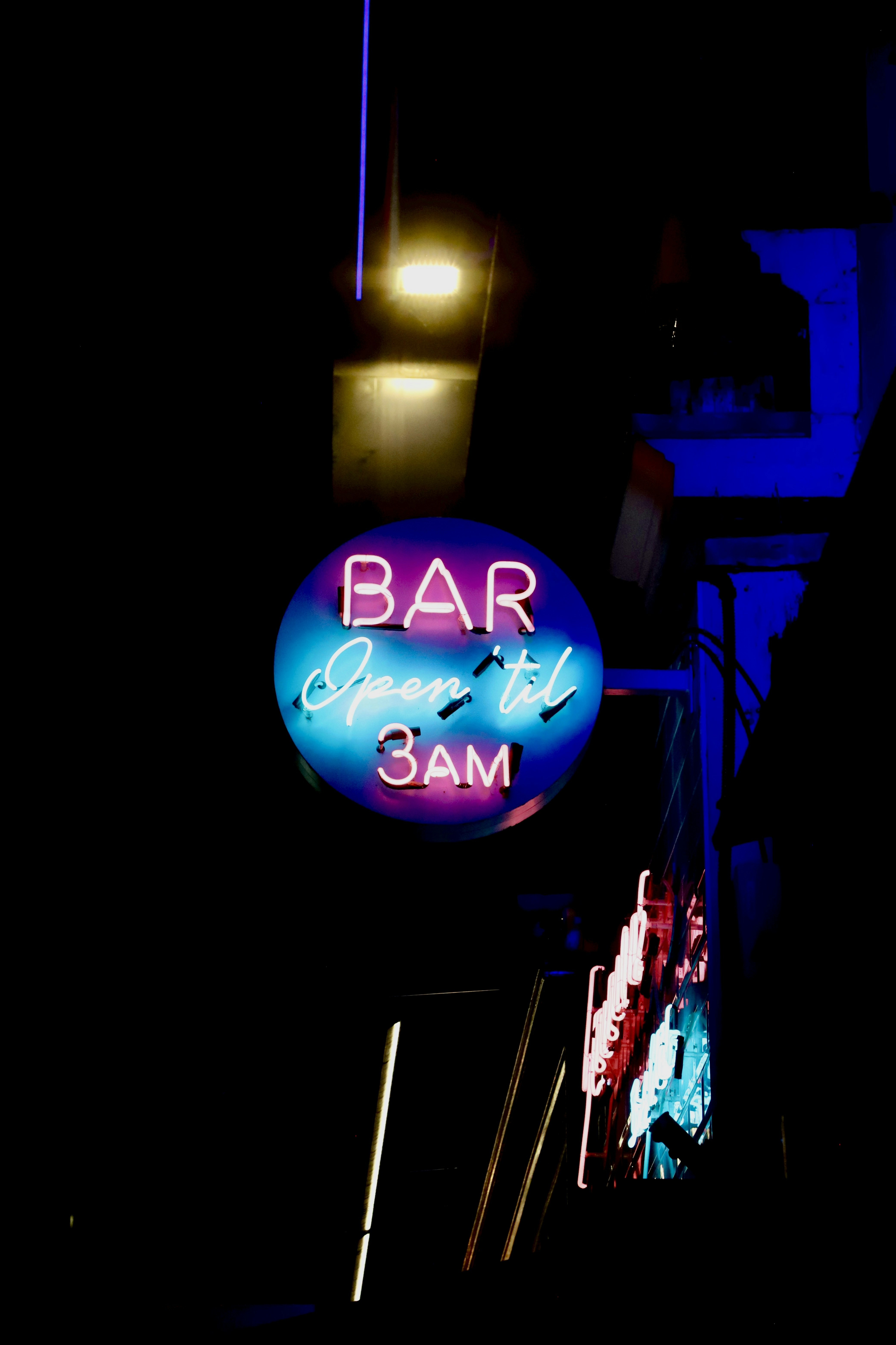 Neon Open Till 3AM: Circular Sign Illuminates a Midnight Alley