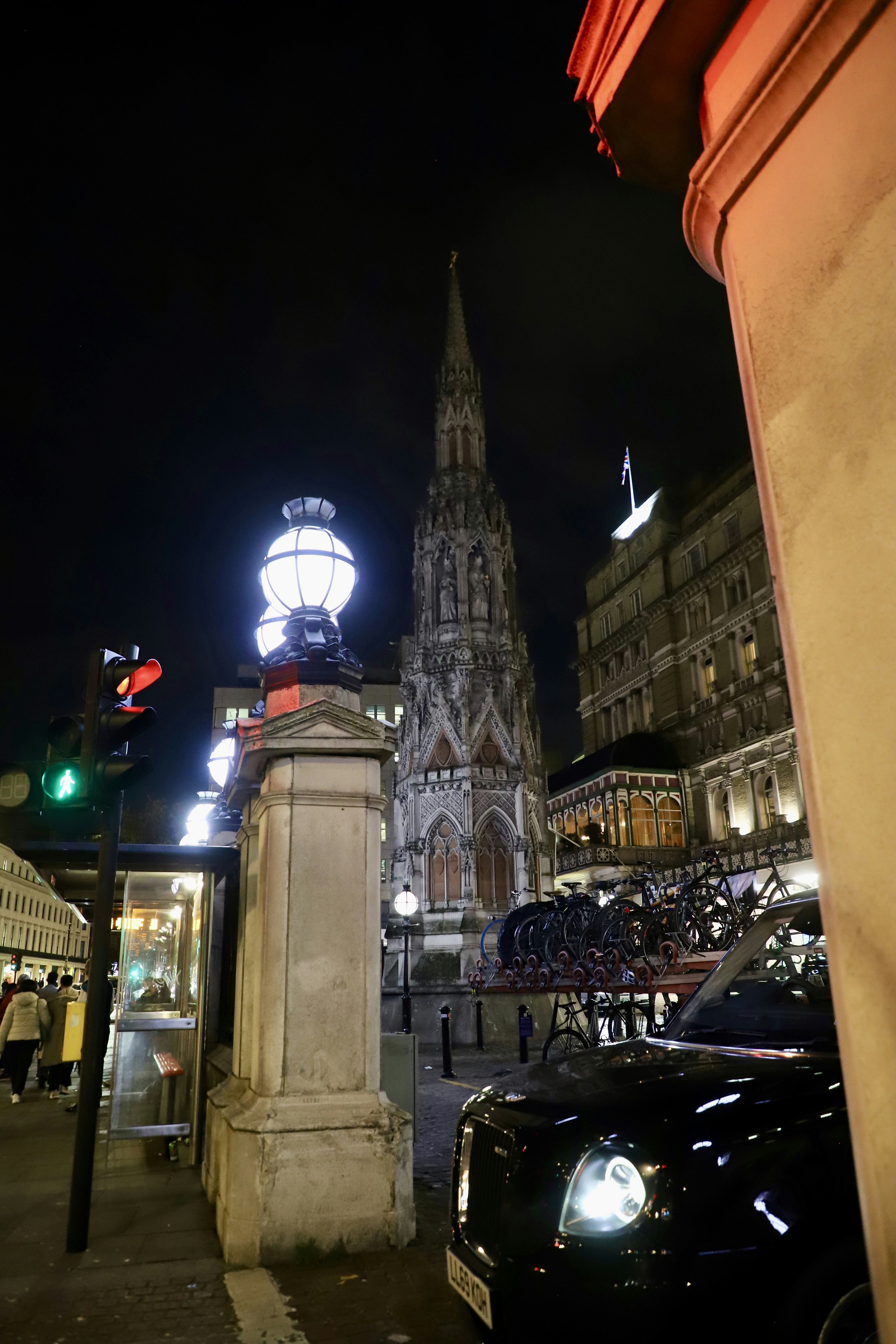 Night Spire on a Busy Street: Gothic Tower Framed by Neon Lamps and a Gleaming Taxi