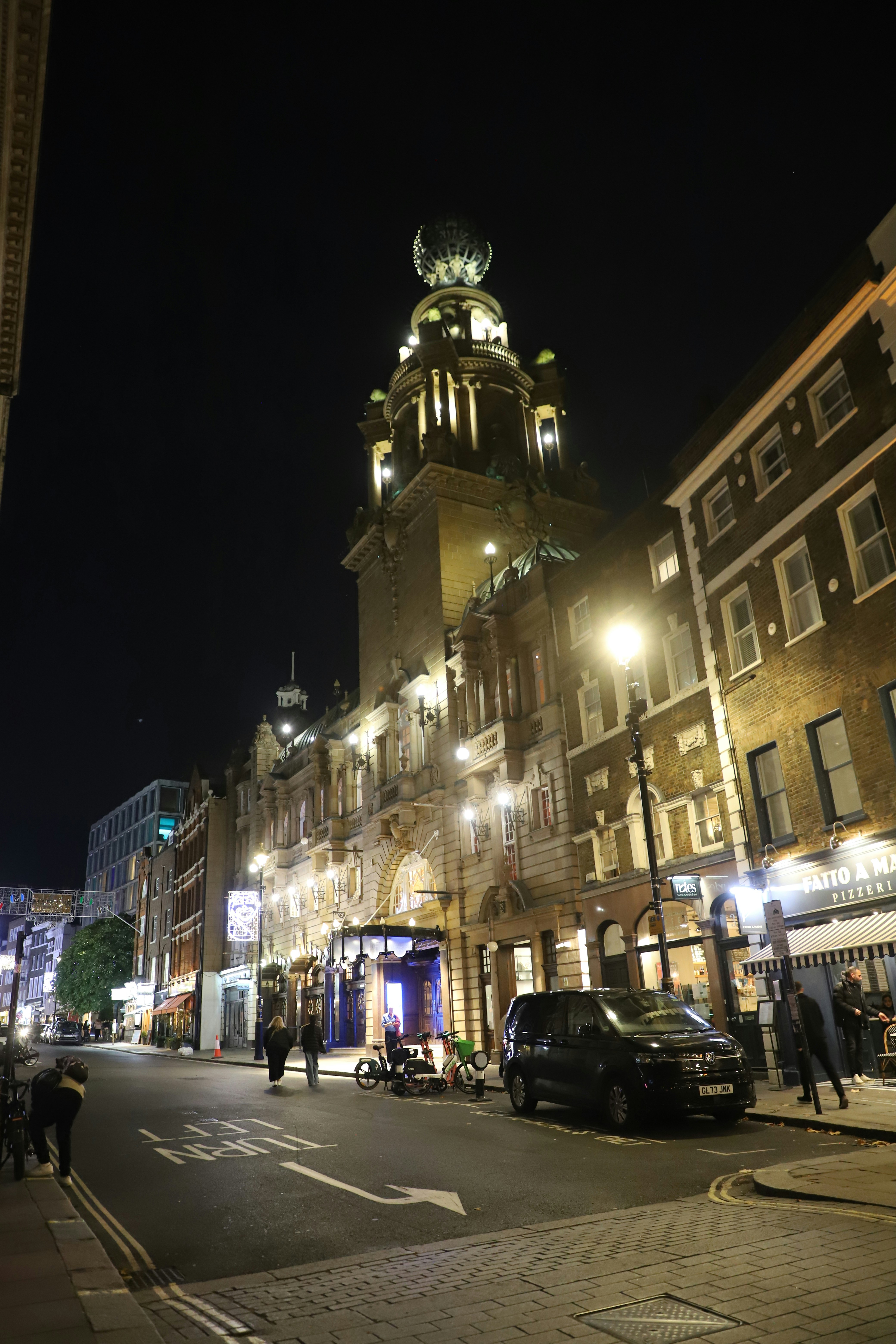 Clocktower Crowned in Light Over a Cobblestone Street