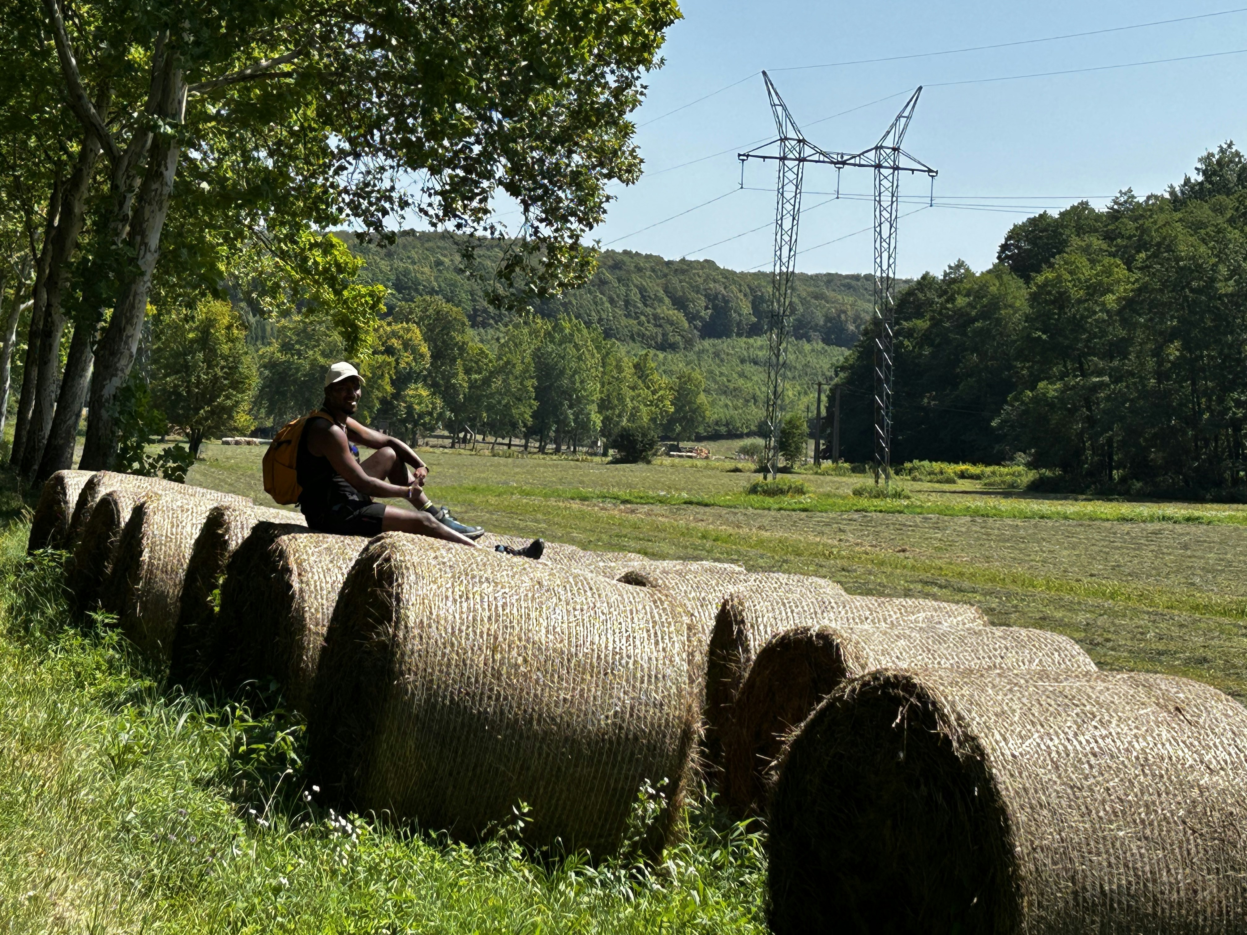 Solitary Rest on a Row of Hay Bales Beneath a Blue Rural Sky