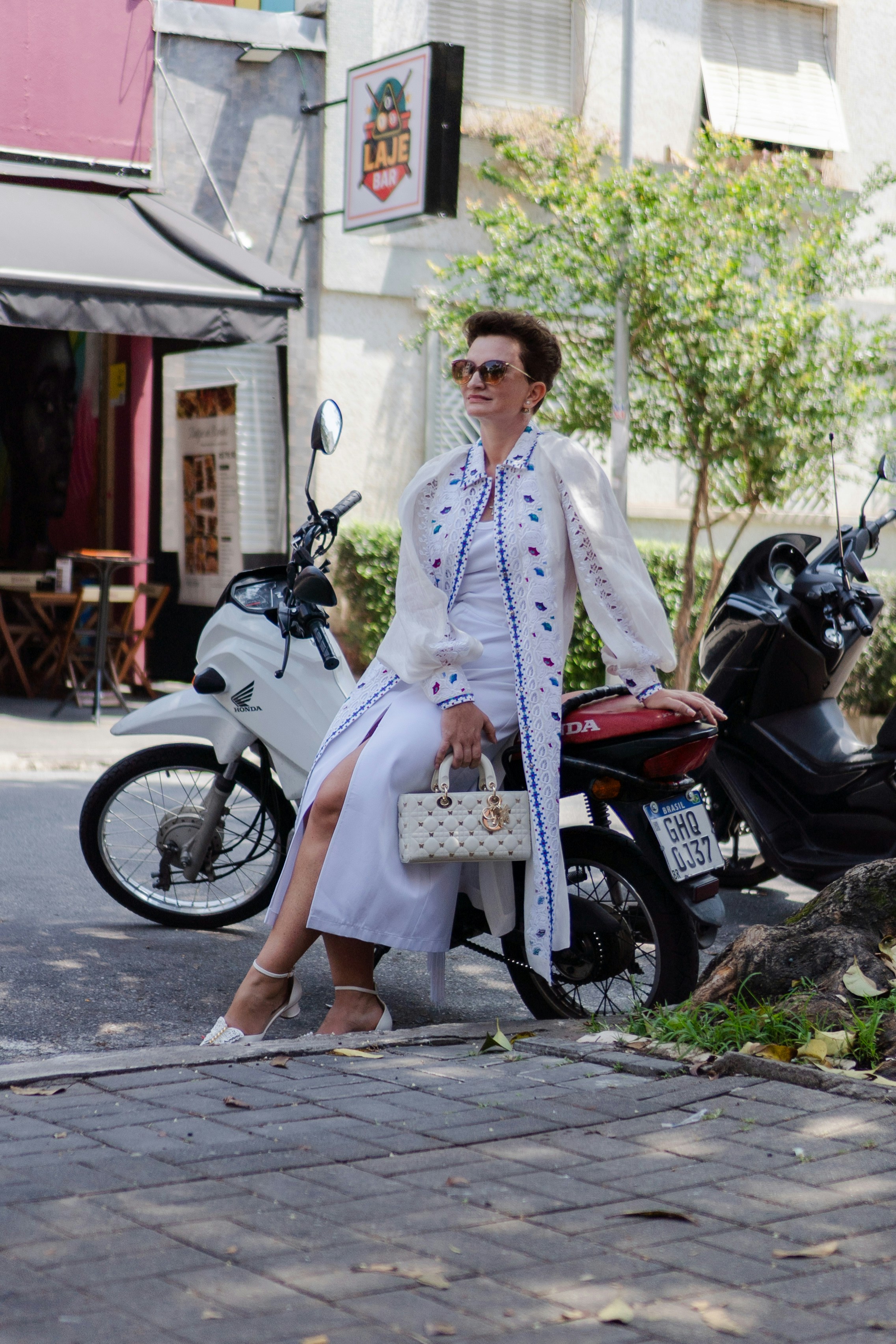 Sunlit Streetstyle: Graceful White Dress Beside Motorcycles