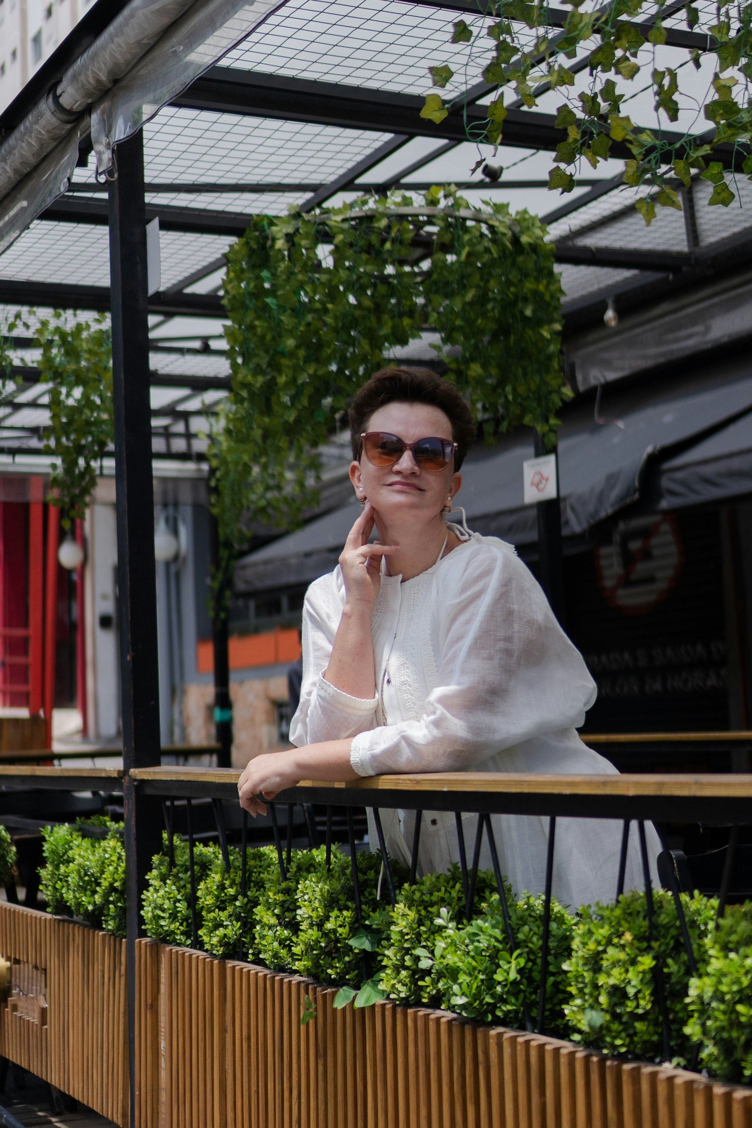 Sunlit Balcony Portrait: Greenery Framing a Confident Pose