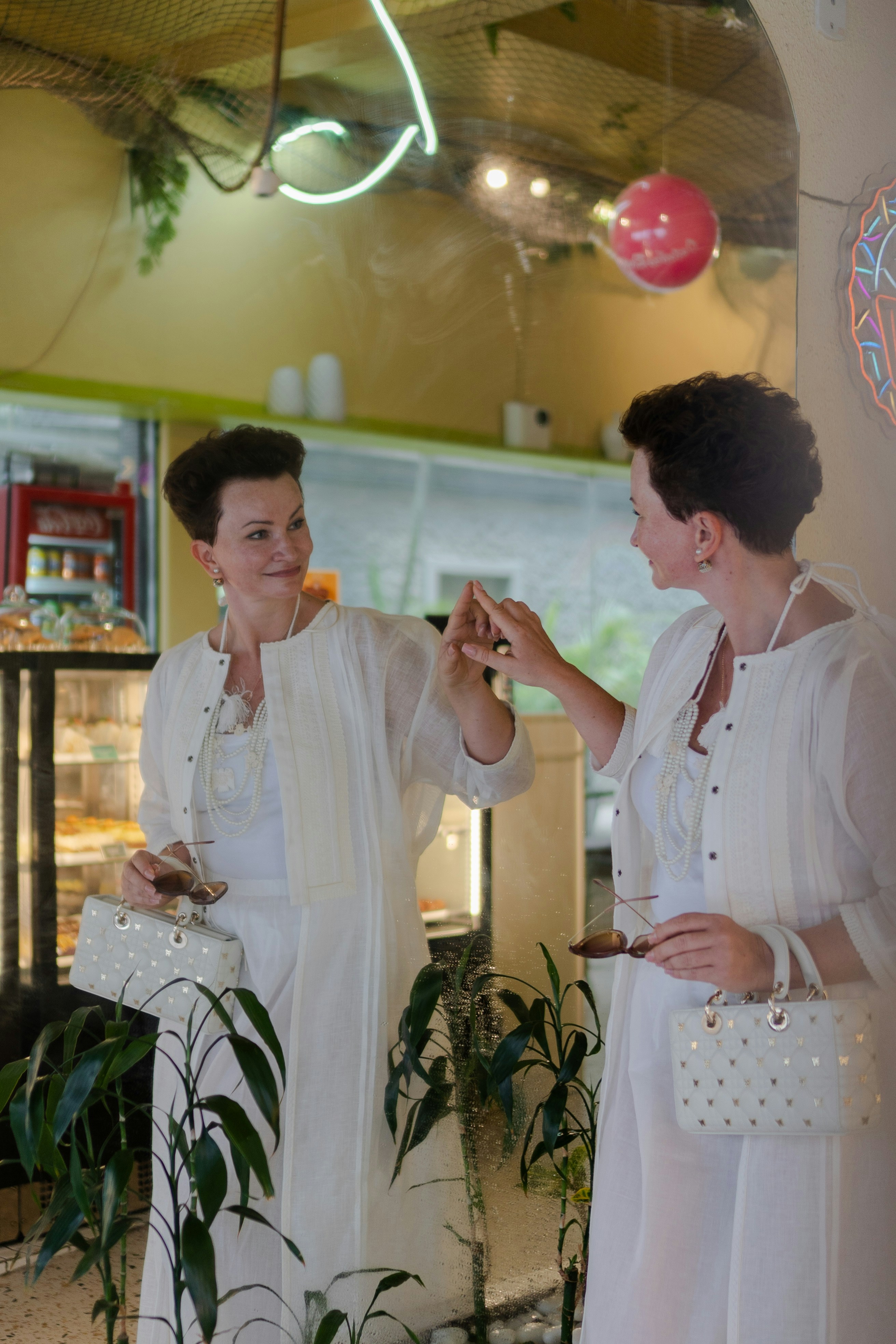 Pastel Café Duet: White Dresses and a Handshake in Soft Neon Light