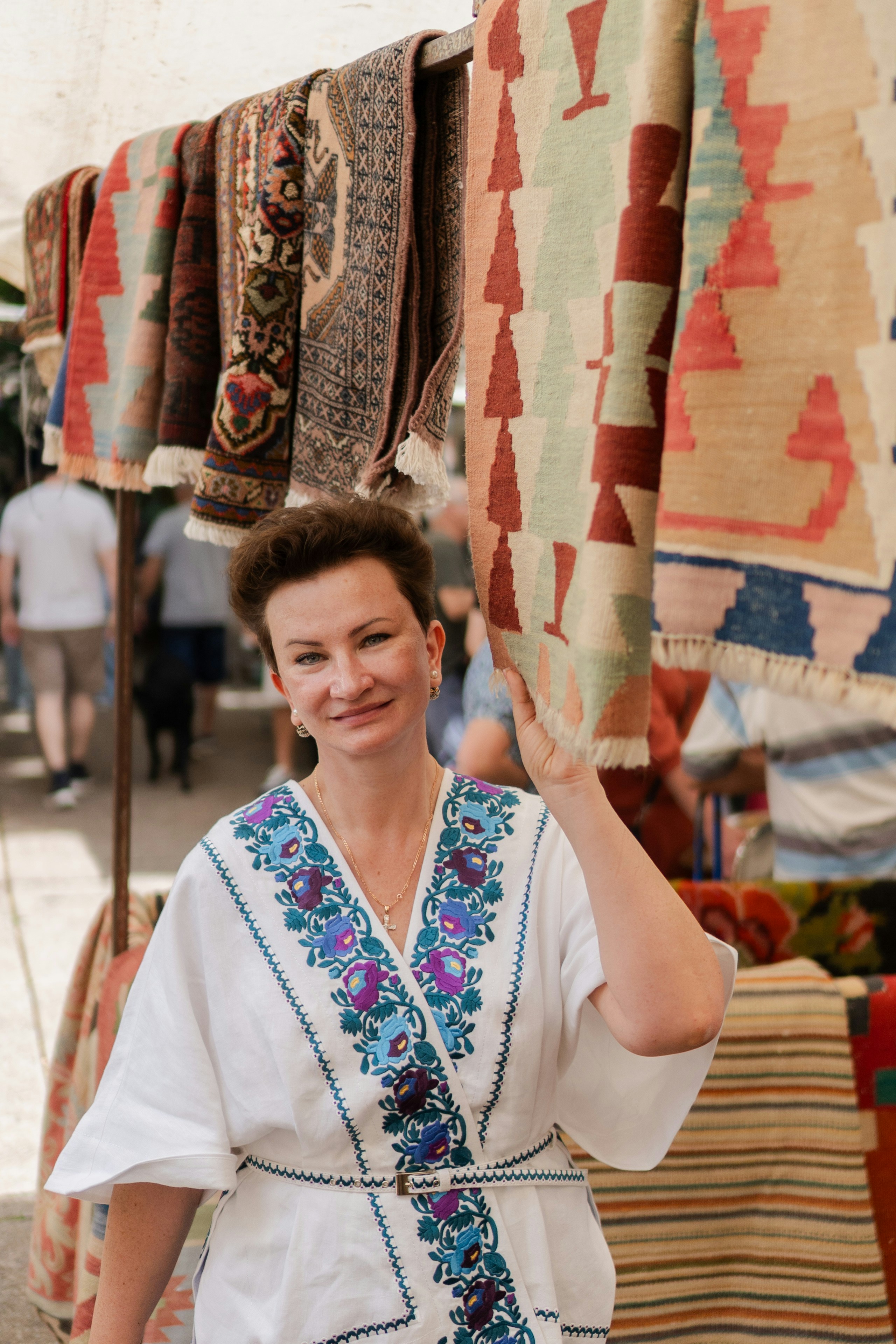 Portrait at a Loom: A Turquoise-embroidered Dress Amid Colorful Rugs