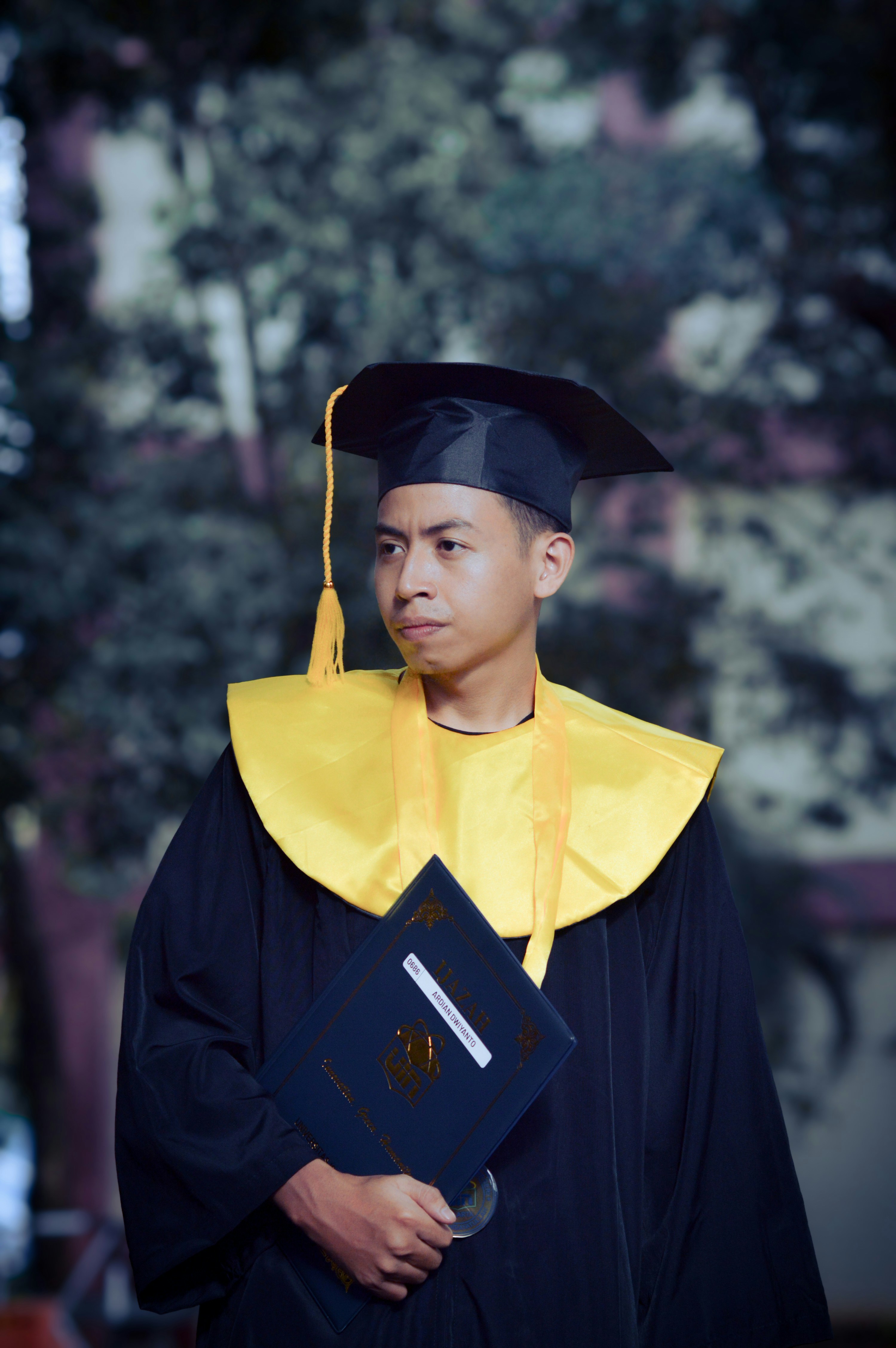 Un jeune homme en toge et casquette de fin d’études tient un diplôme ...