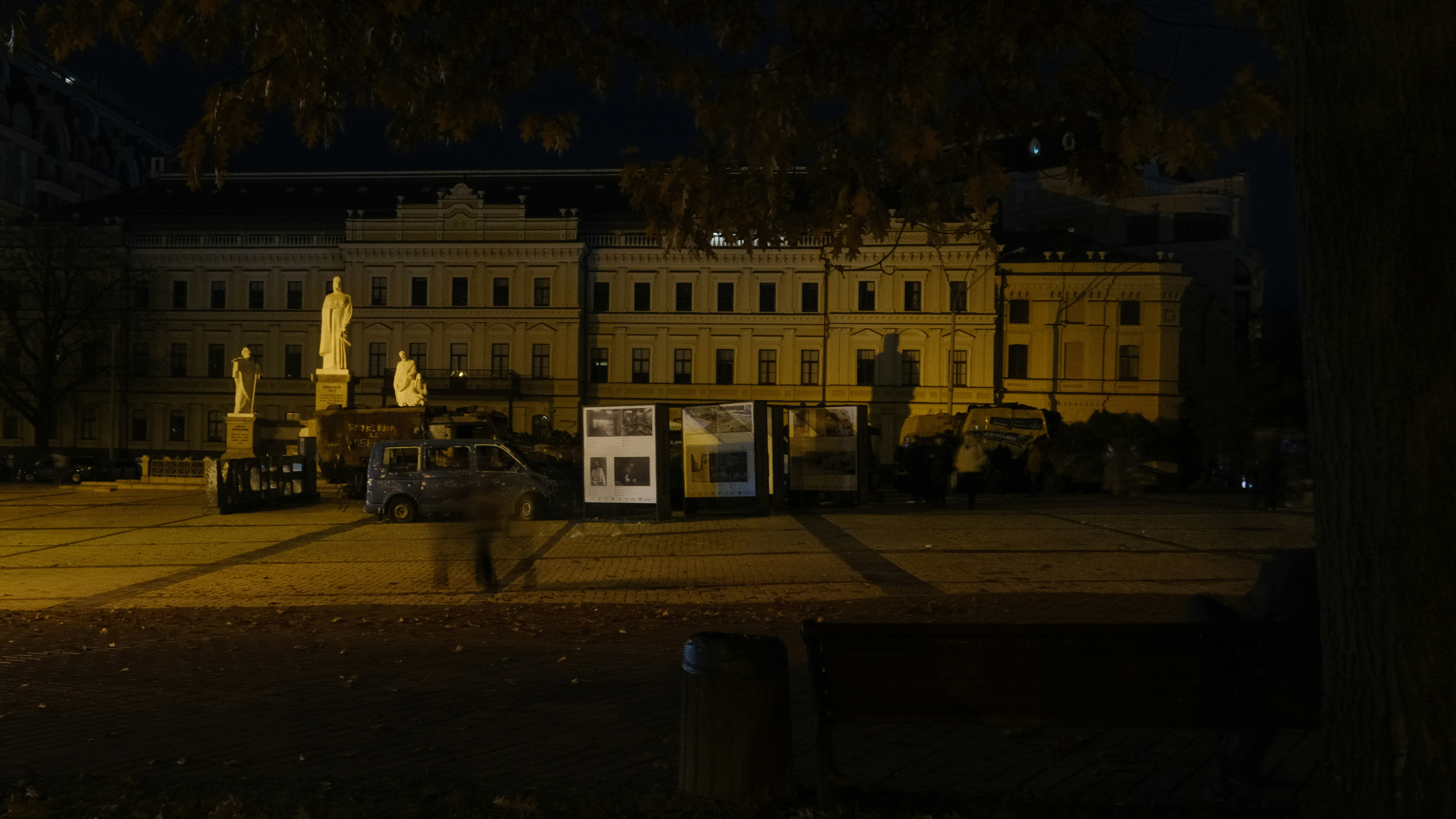 Night Square: Statues, Bus, and Illuminated Facade