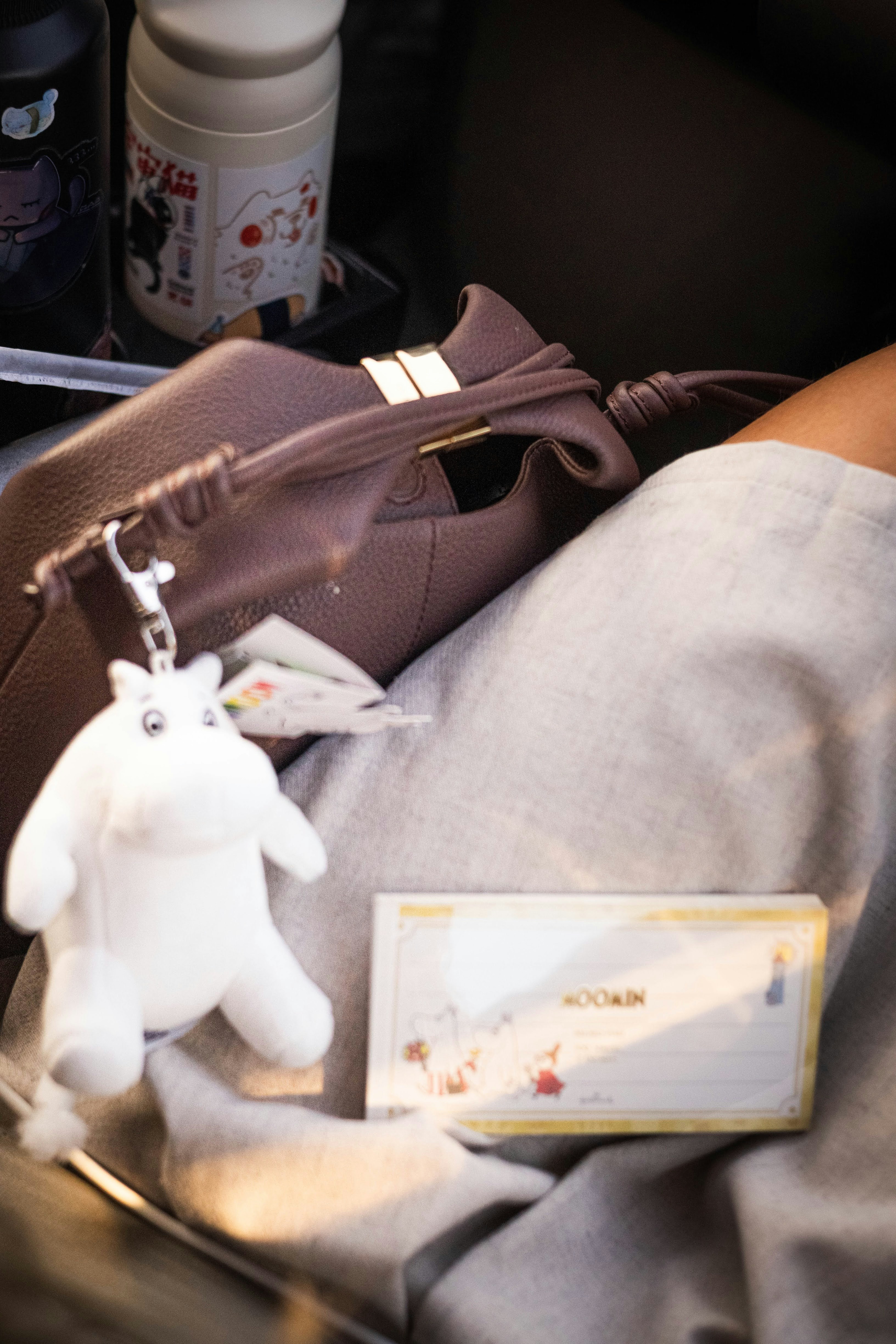 Snowy Plush Keychain Dangles from a Brown Tote in a Quiet Car Interior
