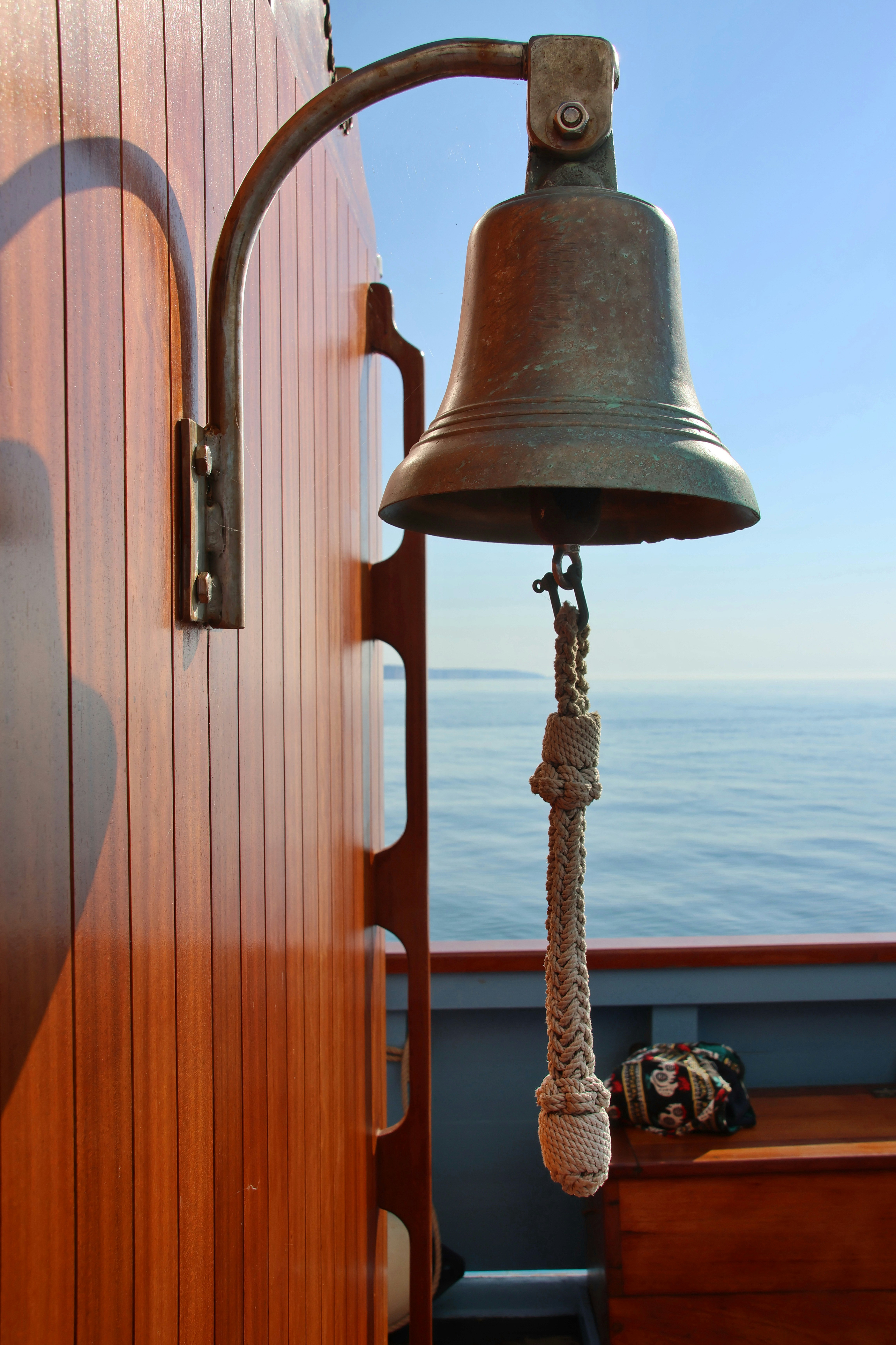 Bronze Ship Bell on a Seaside Deck: Knot and Quiet Horizon