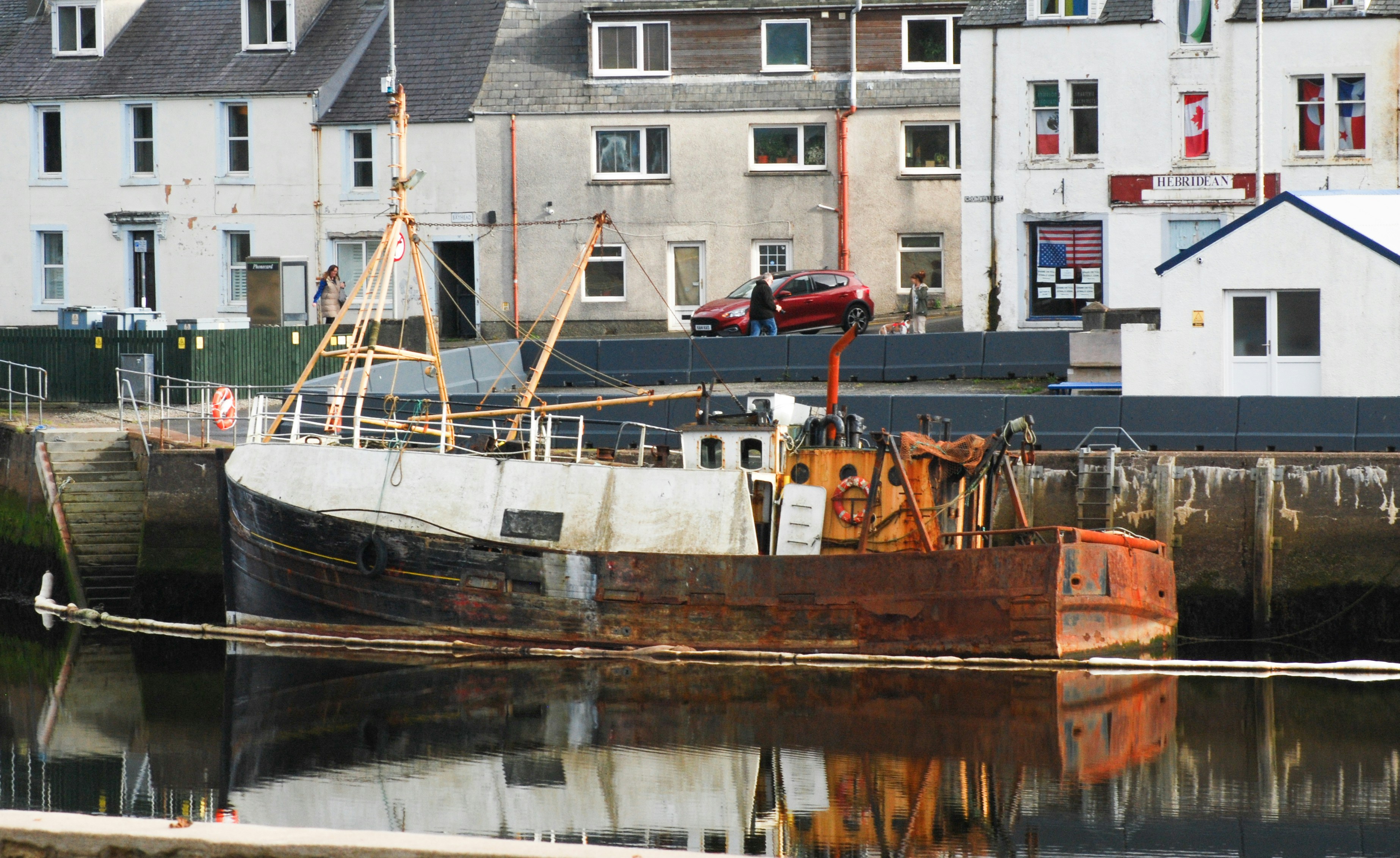 Rusted Barque by a Quiet Harbour: Reflections Across a Calm Waterfront