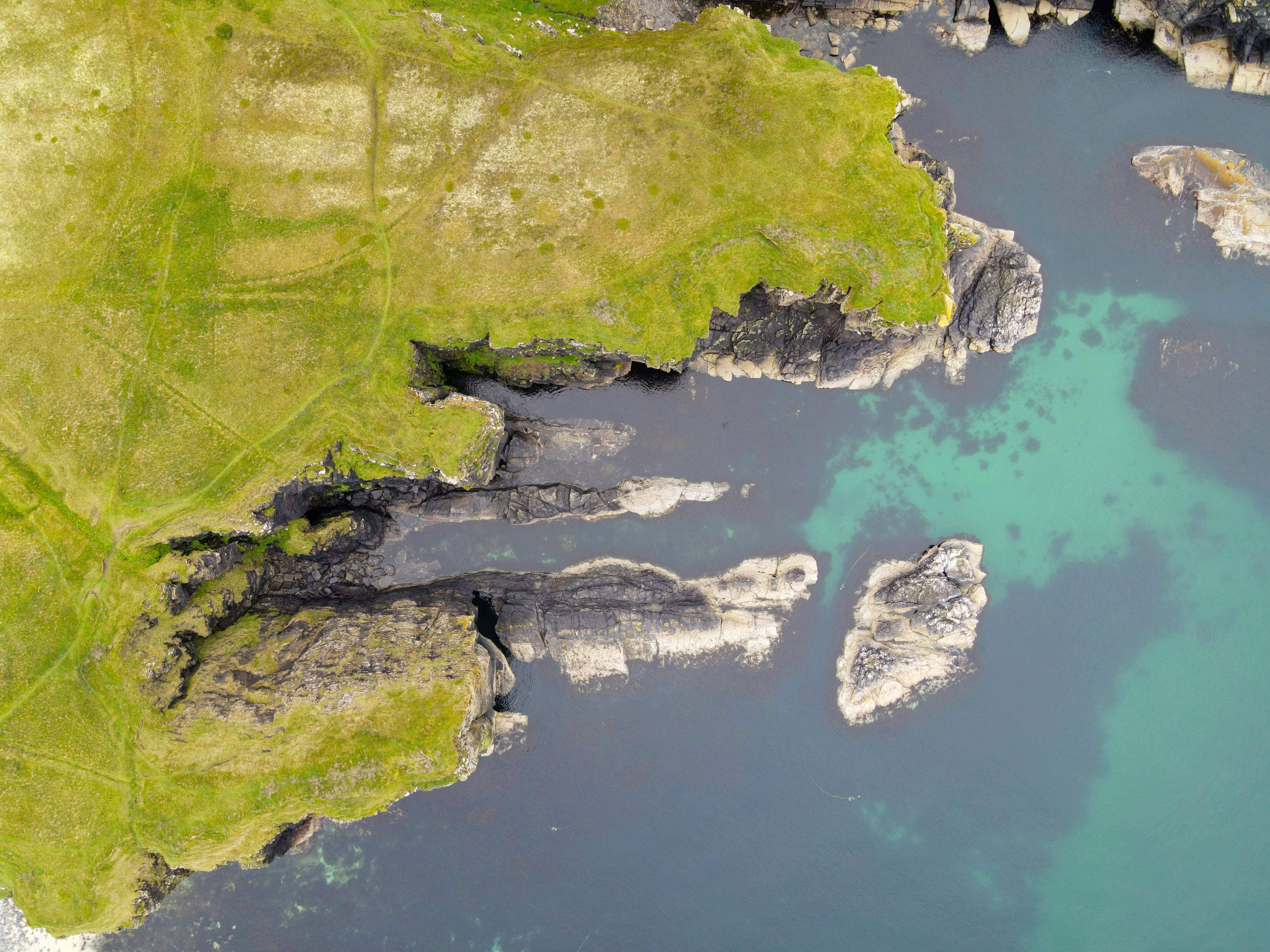 Emerald Edge: Grass-Covered Cliffs Framing a Turquoise Inlet