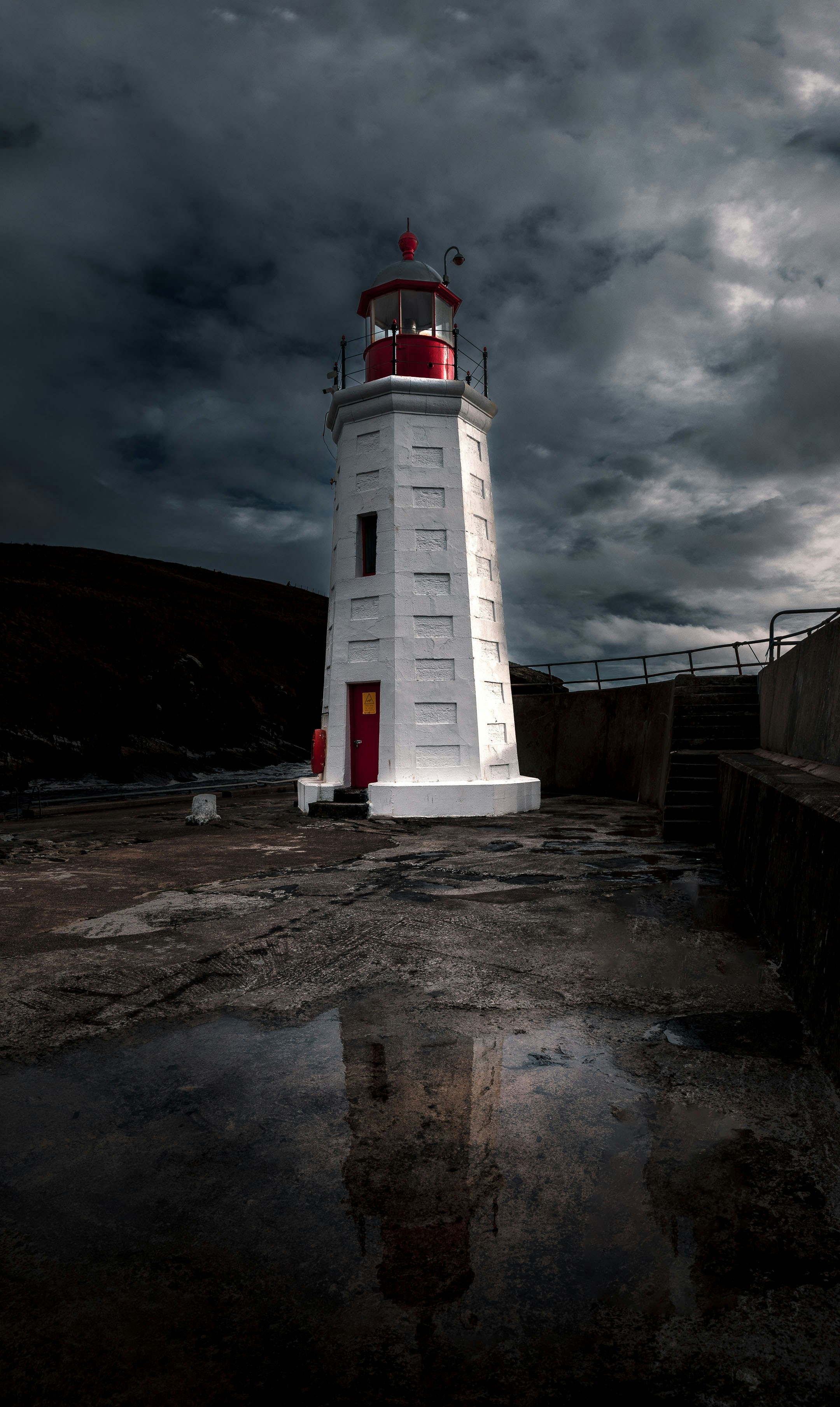 Lybster Lighthouse reflected in a puddle under a dramatic Scottish sky. This moody coastal photograph captures the power of light, weather, and reflection — perfect for lovers of dramatic seascapes and atmospheric wall art.
