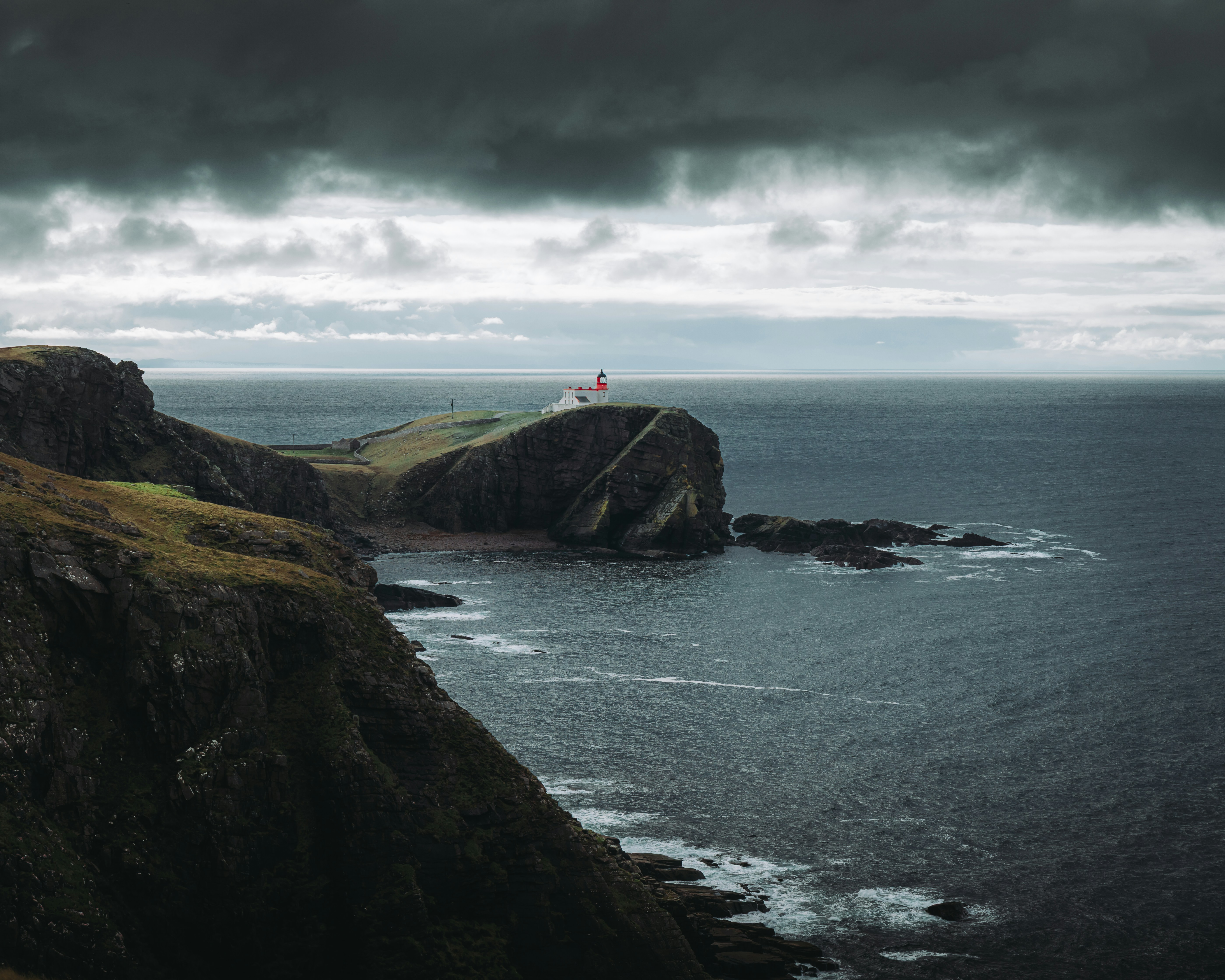 Lighthouse perched on the edges of cliffs in Scotland.