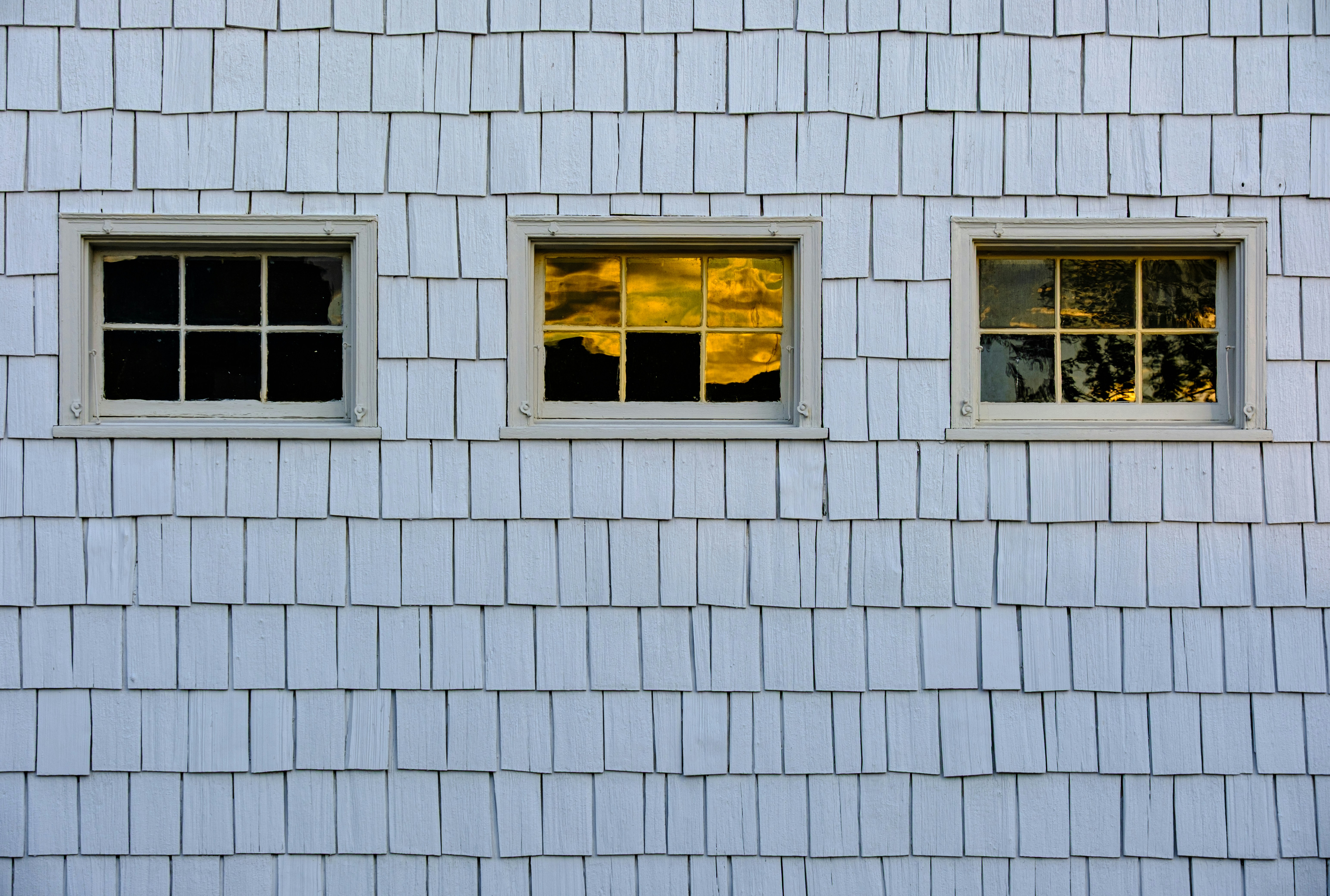 The Center Pane: A Quiet Sunset Glimmer in a Wall of White Shingles