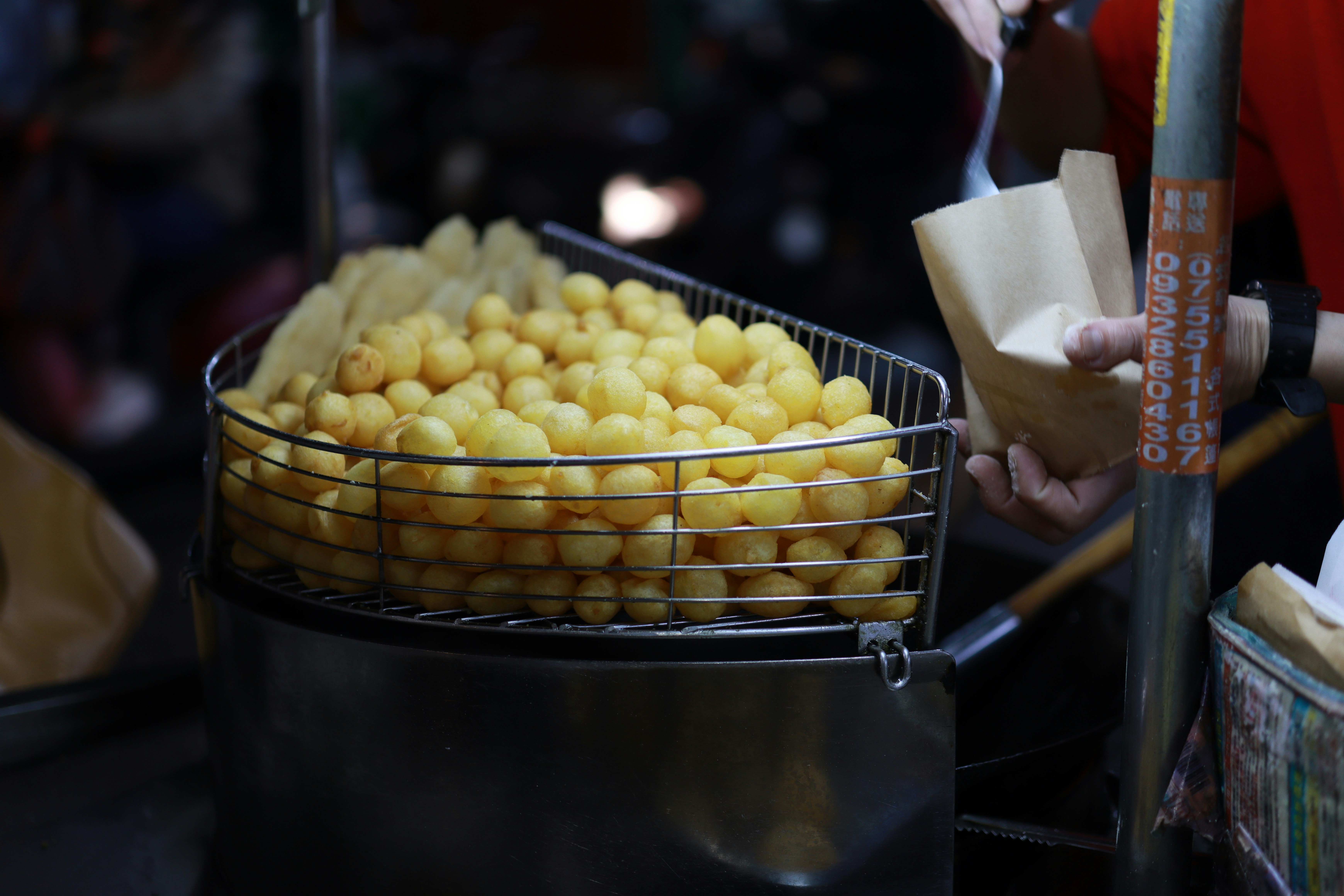 Moonlit Crunch: Basket of Golden Cheese Balls at a Street Fryer