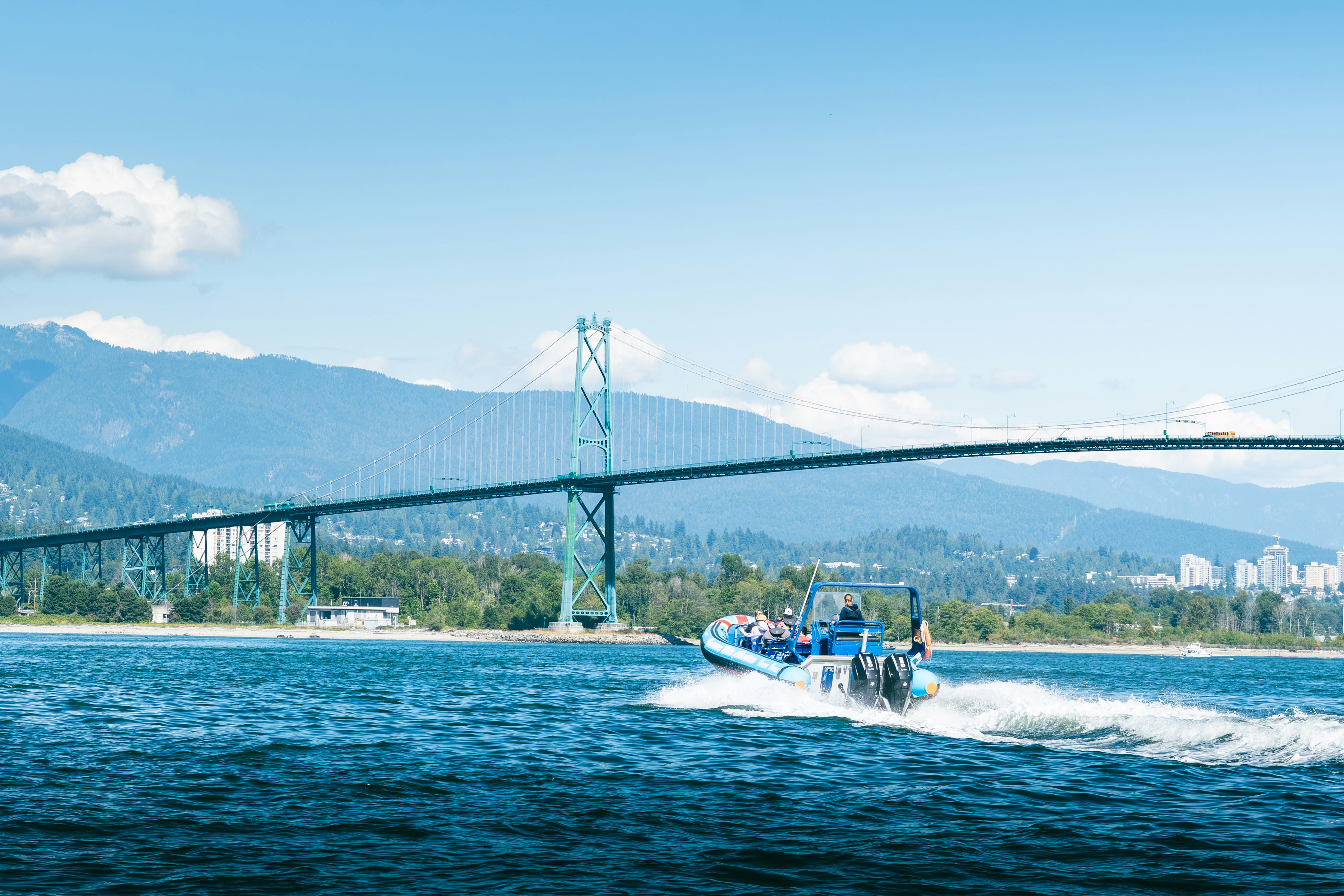 Blue Wake Under the Steel Arc: Speedboat Slice by a Coastal Bridge