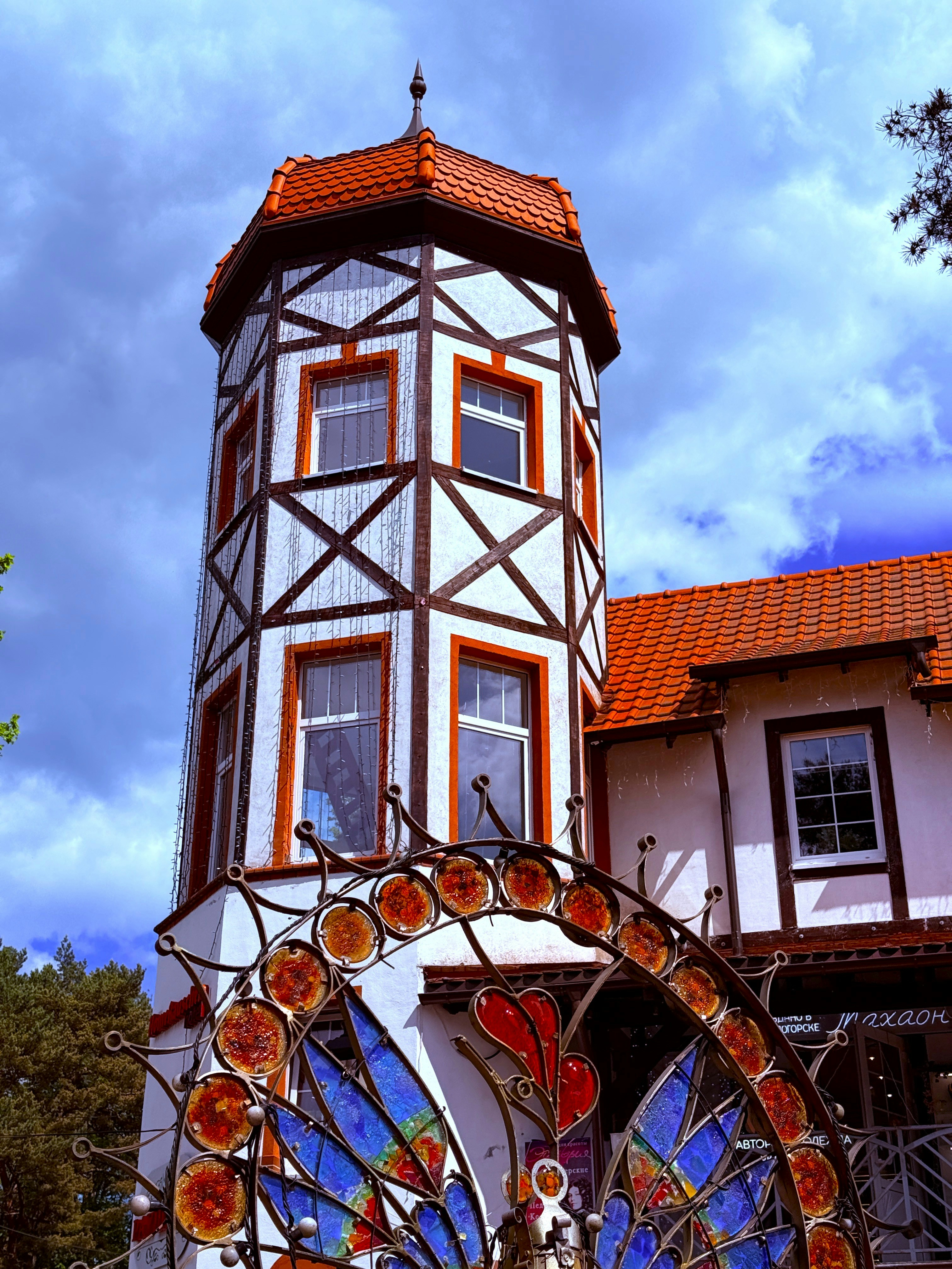 Half-Timbered Turret with Terracotta Roof, Framed by a Circular Glass-Flower Gate