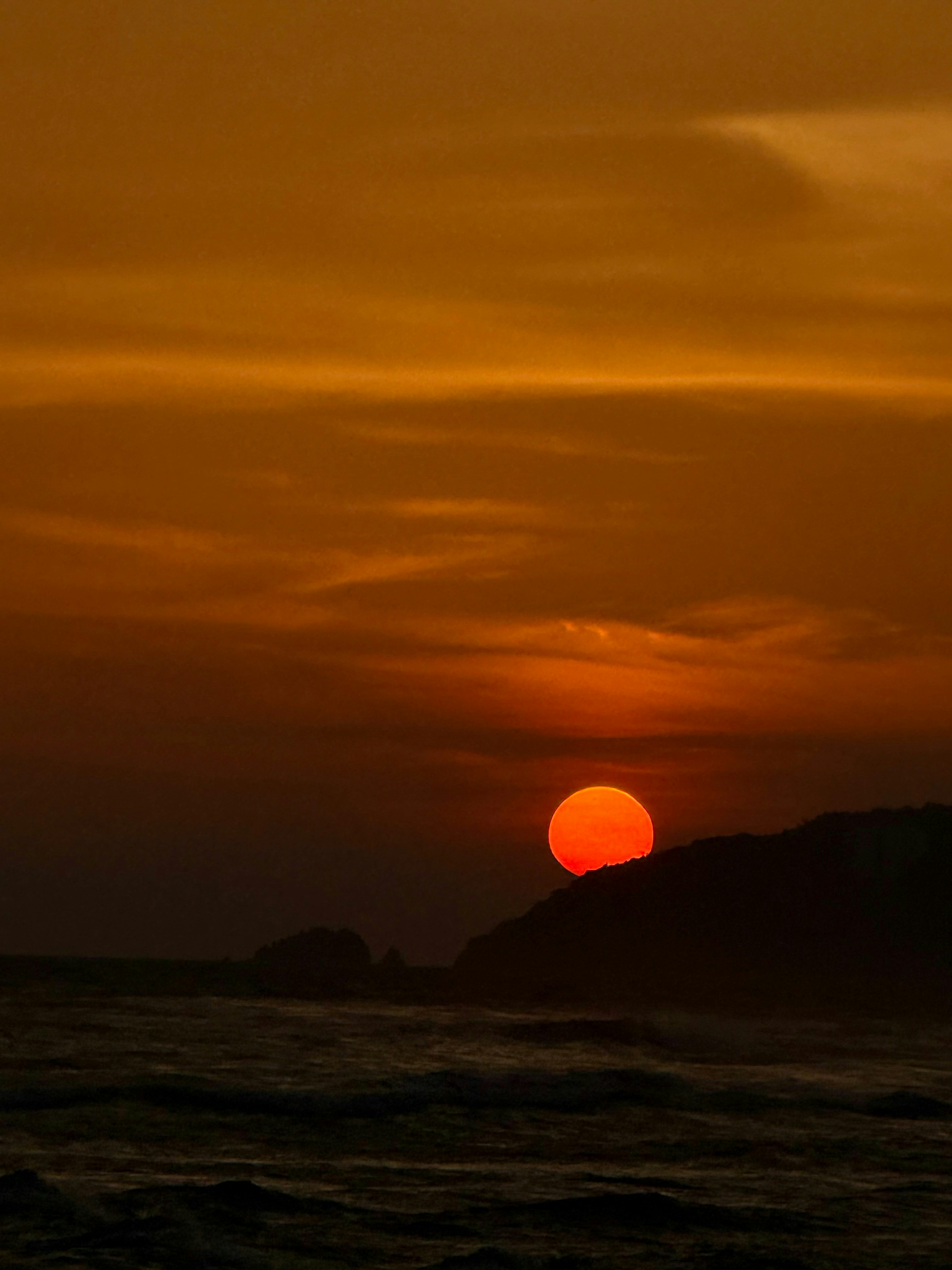 Crimson Sun Dropping Behind the Silhouette Ridge at Dusk
