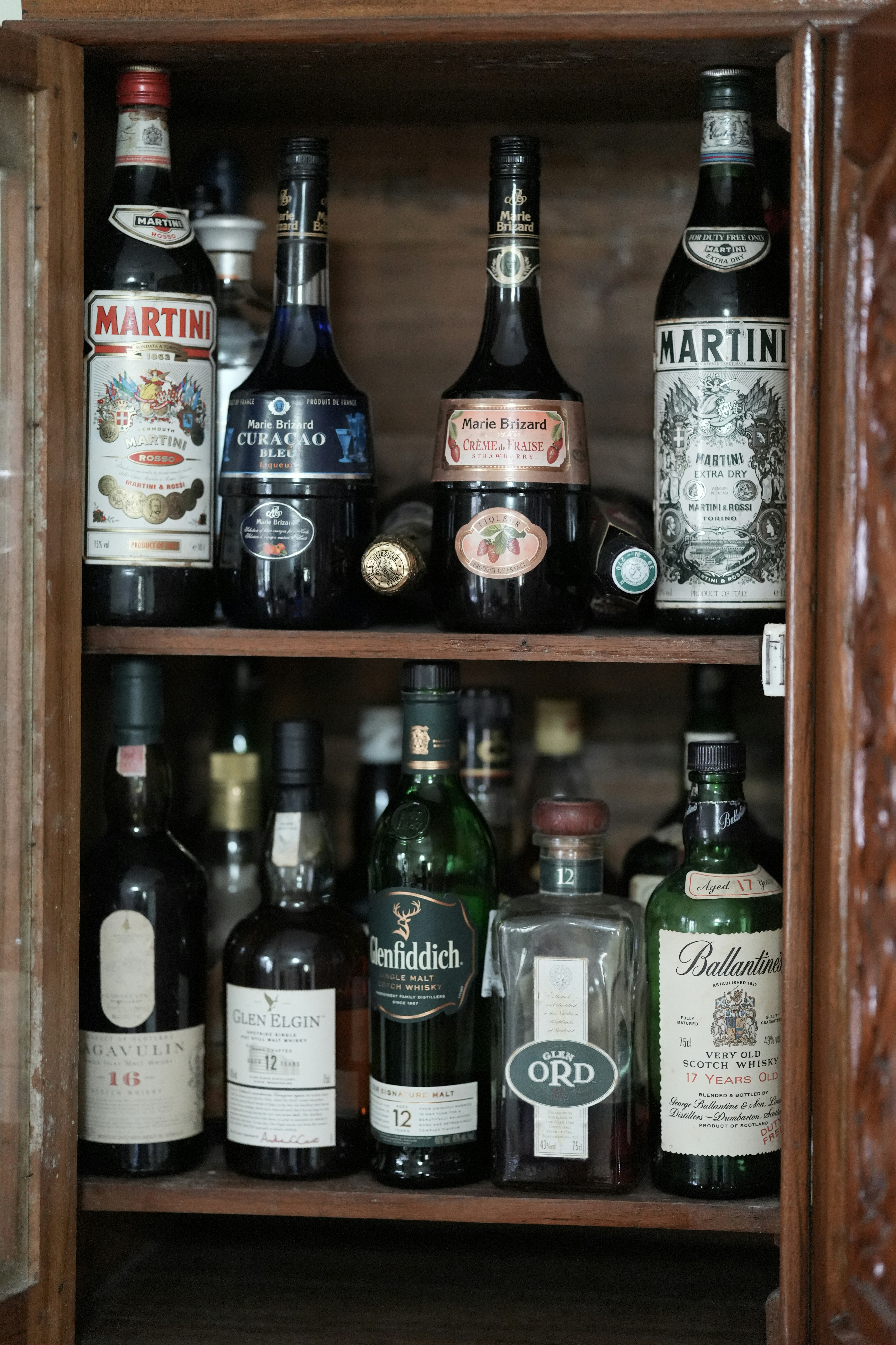 Centerpiece on Walnut: Bottled Histories Rest on a Quiet Cabinet