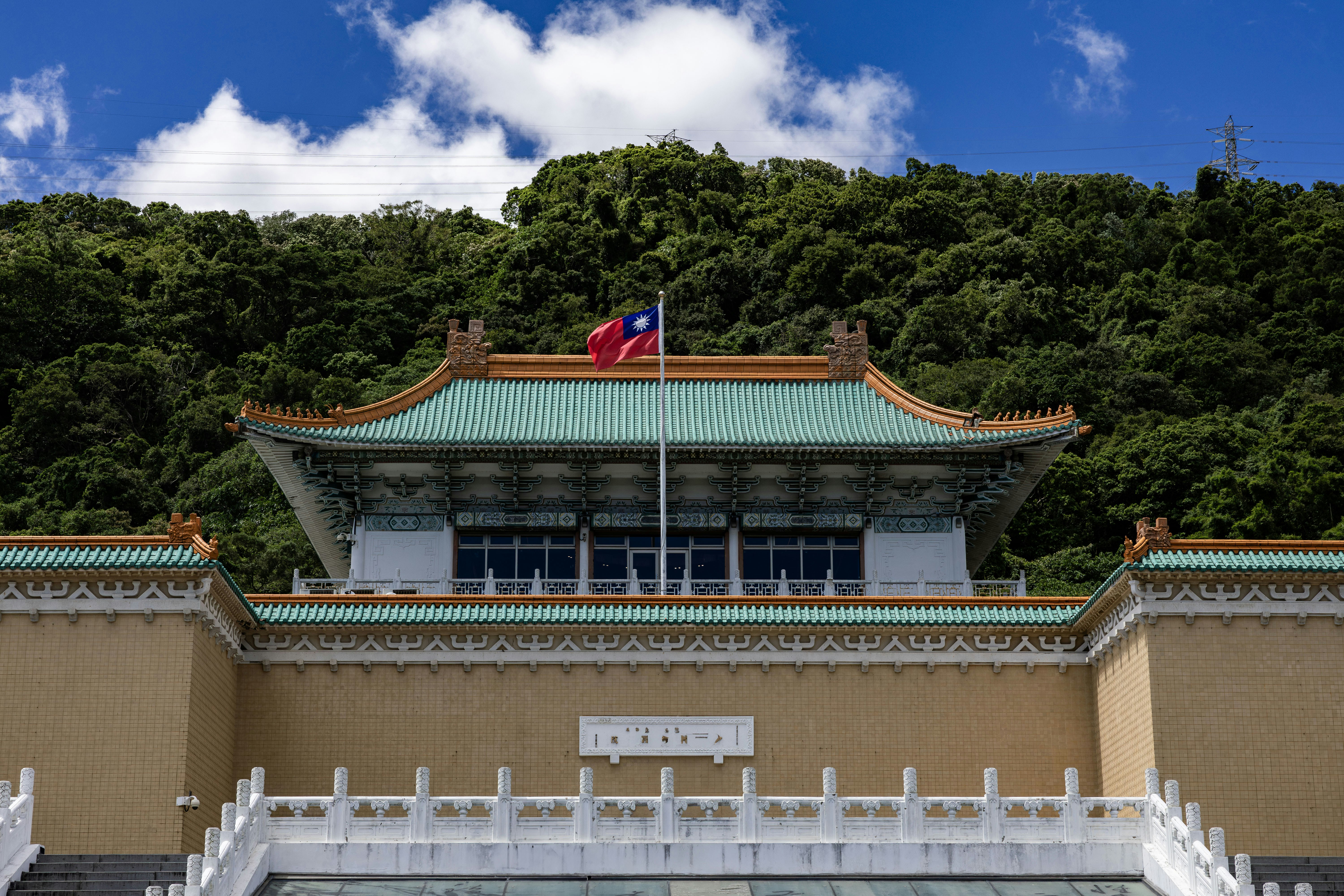 Flagpole Above the Temple Gate, Framed by Verdant Hills and Azure Sky