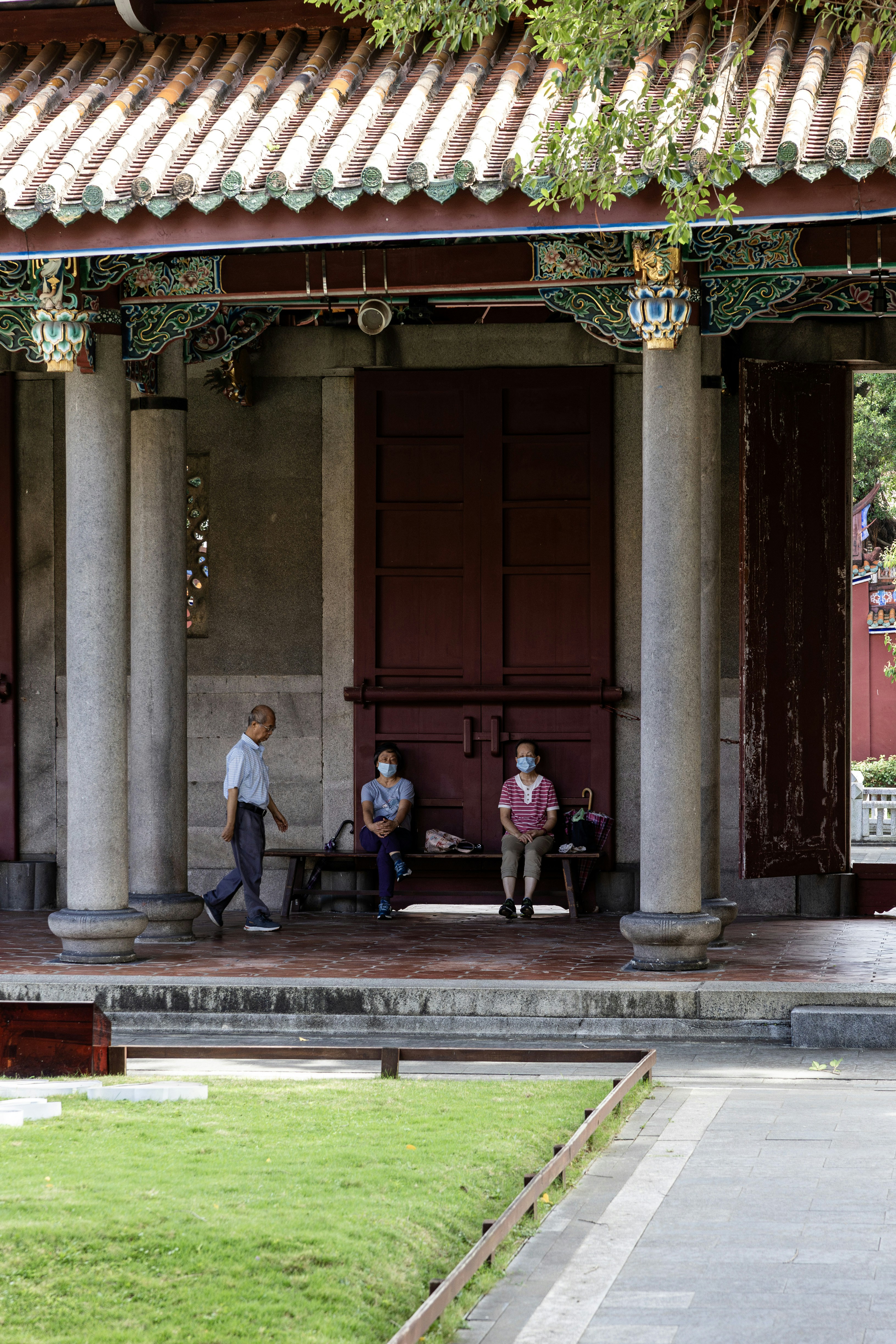 Masked Stillness on a Temple Veranda: Quiet Portrait Among Stone Columns